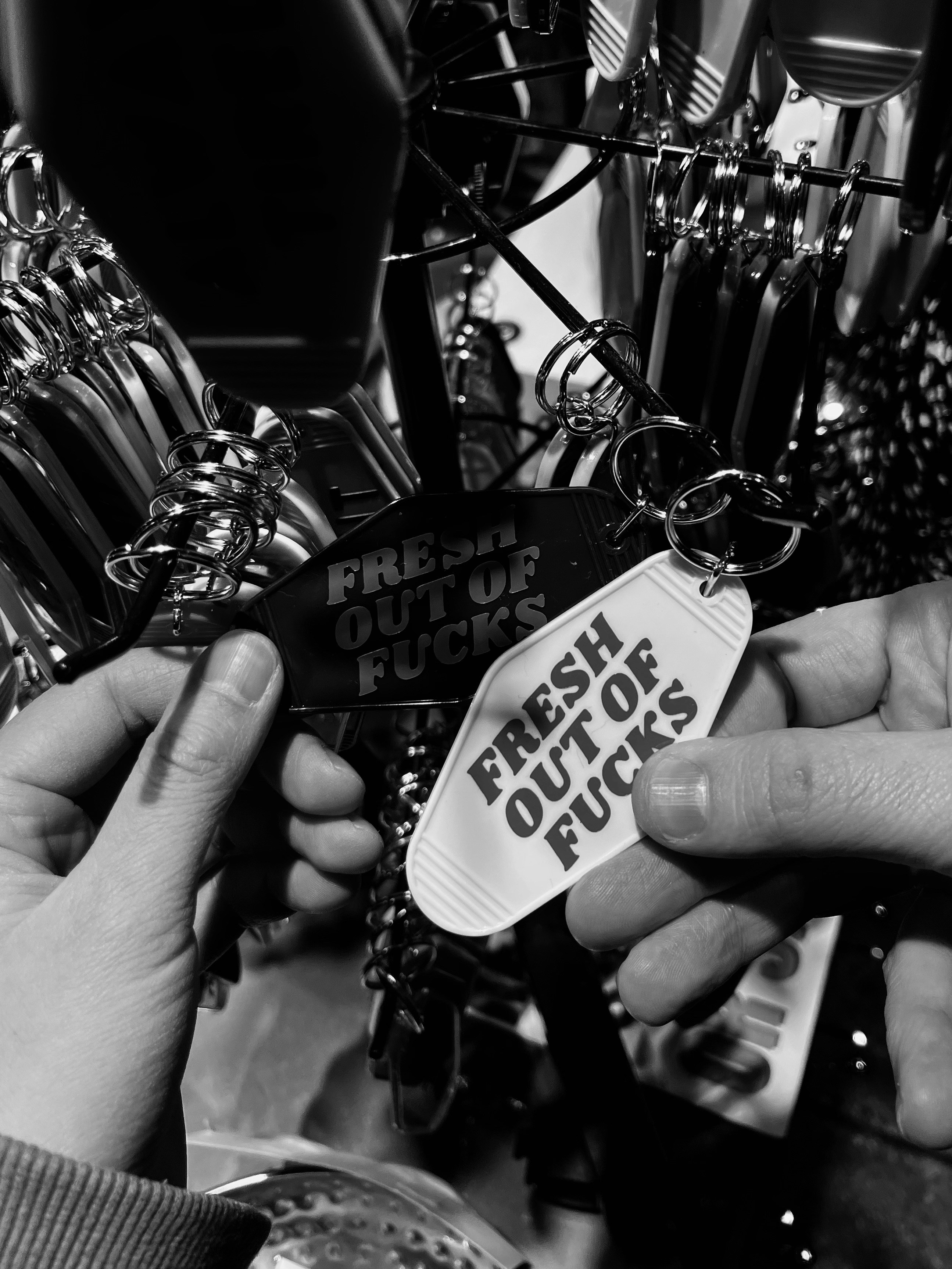 Fresh Out of Fucks: Close-Up of Bold Tag Keychains Entangled in Chrome