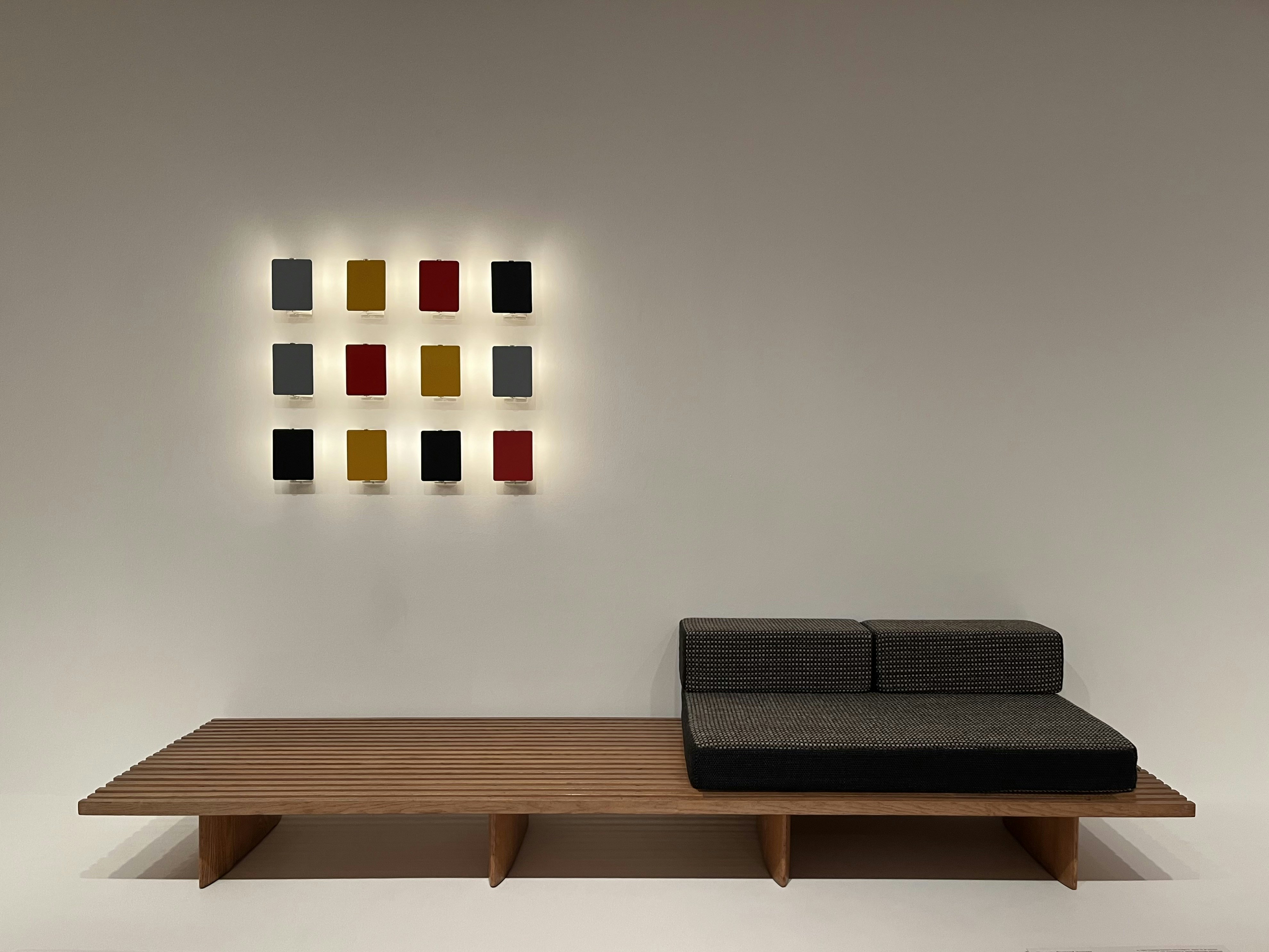 A Quiet Gallery of Color Tiles Hovering Above a Minimal Wooden Platform Bench