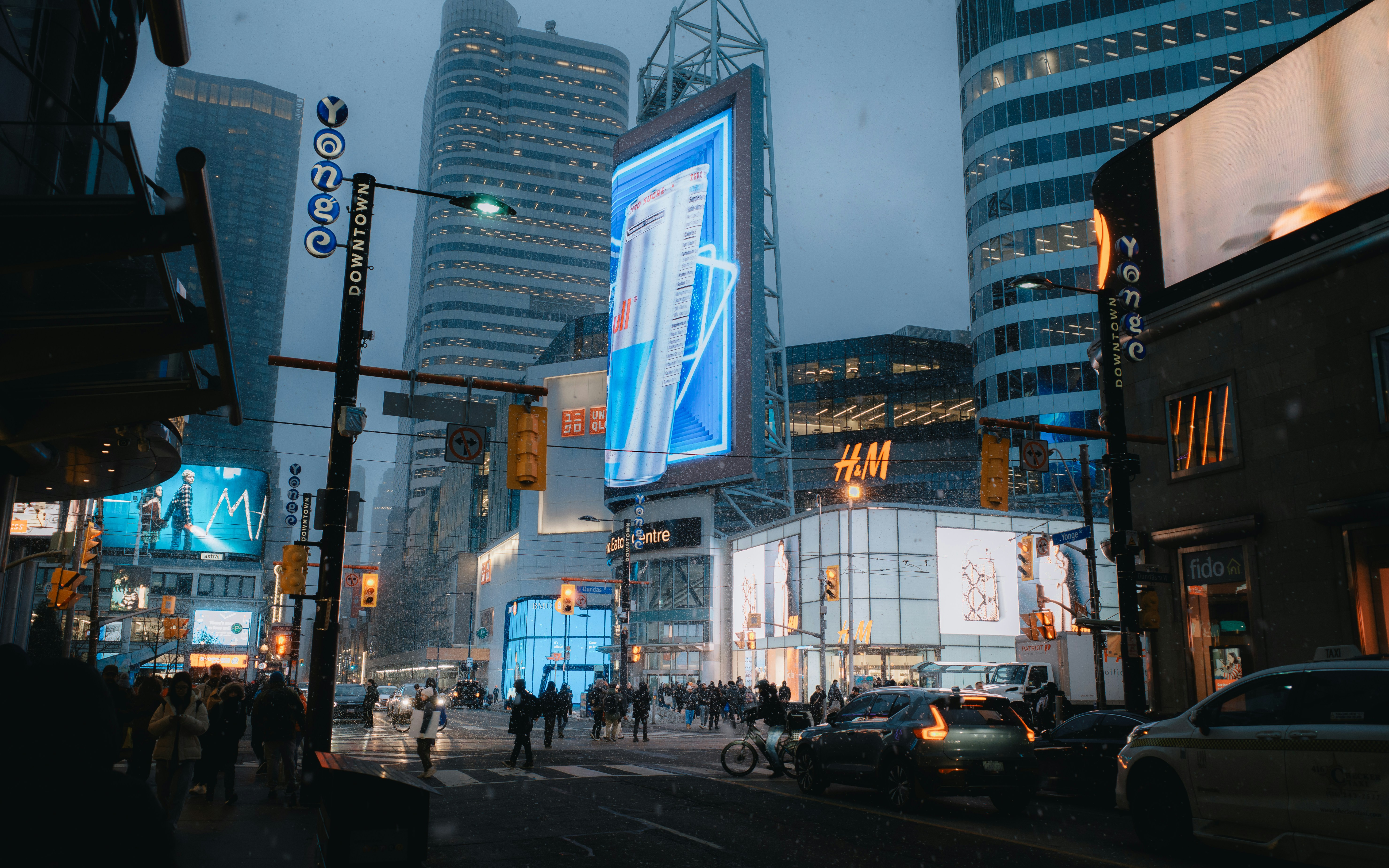 Busy city intersection with colorful billboards and skyscrapers at dusk, blending cool digital hues with warm streetlights.