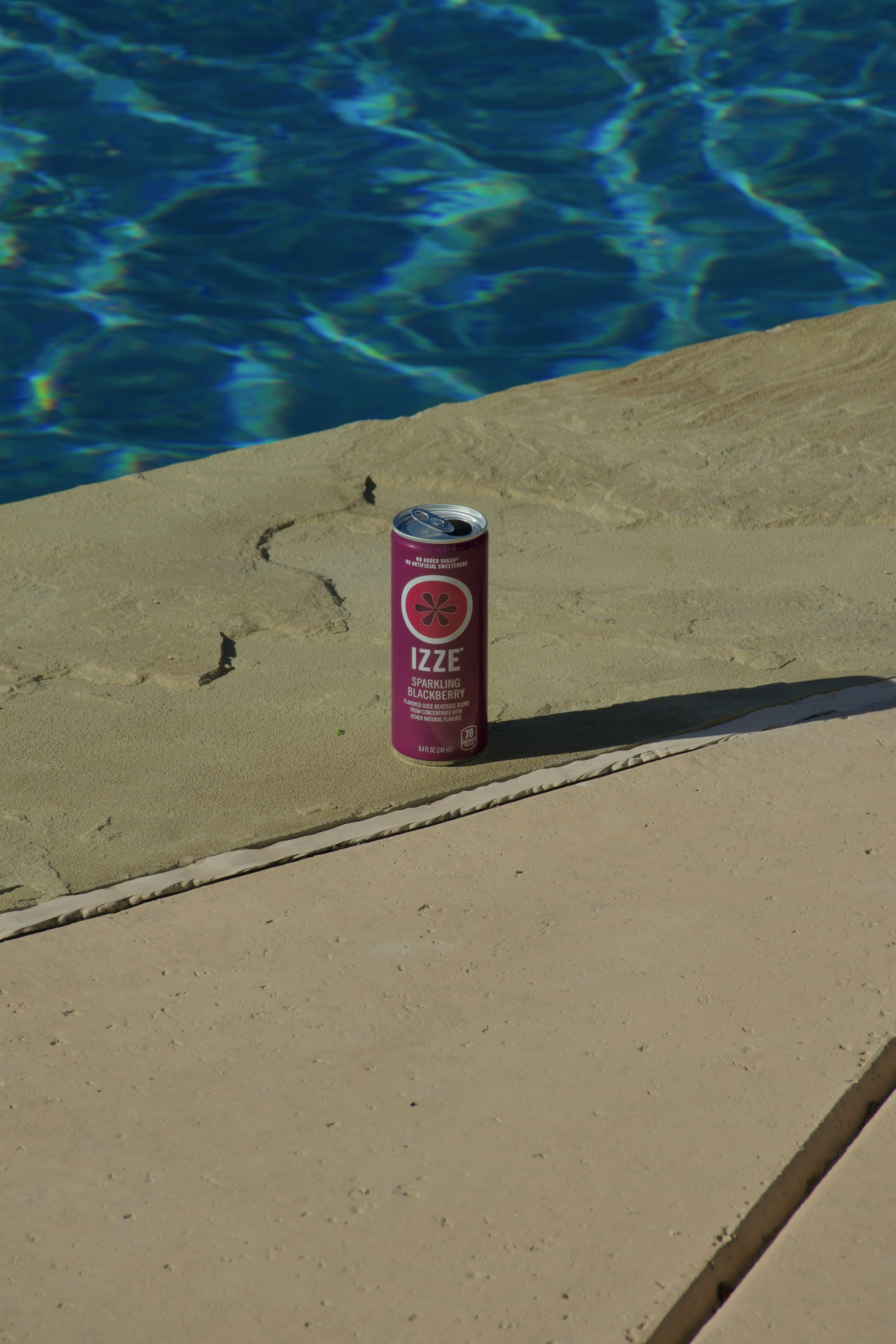 A can of soda sitting on the edge of a pool photo – Free Drink Image on ...