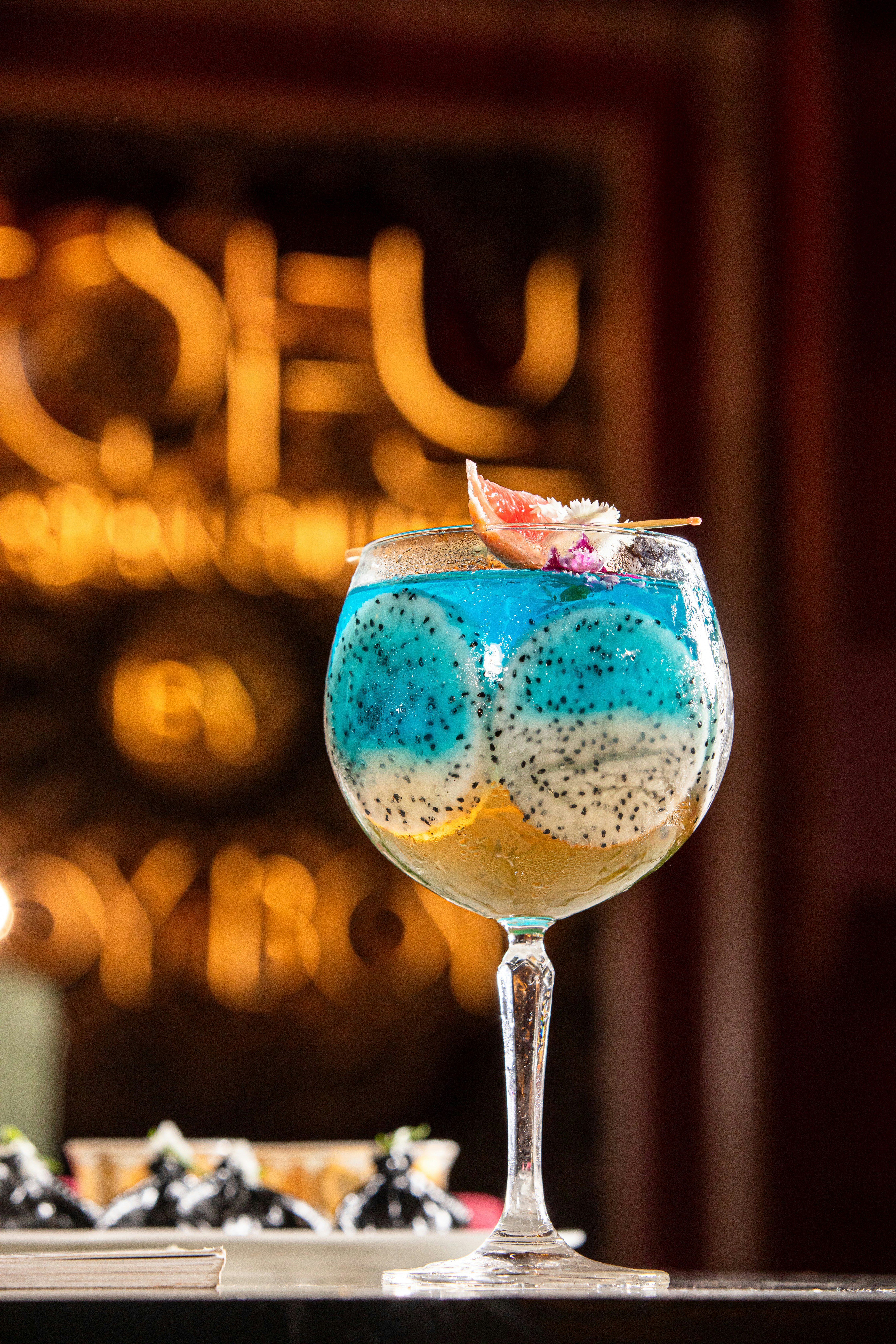 Azure Tango in a Goblet: Layered Cocktail with Citrus Garnish
