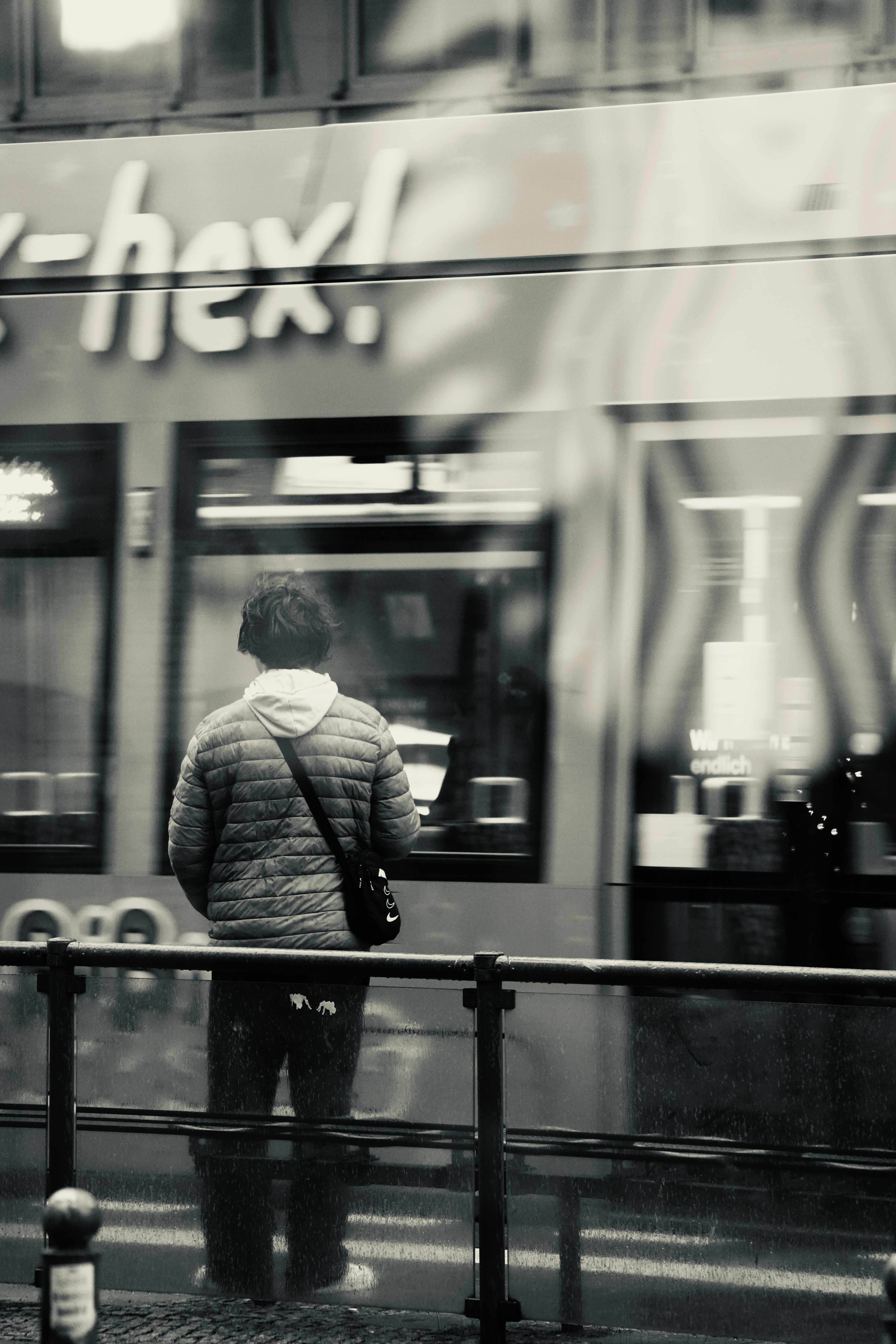 Monochrome Moment: A Lone Figure Framed by Blurred Transit