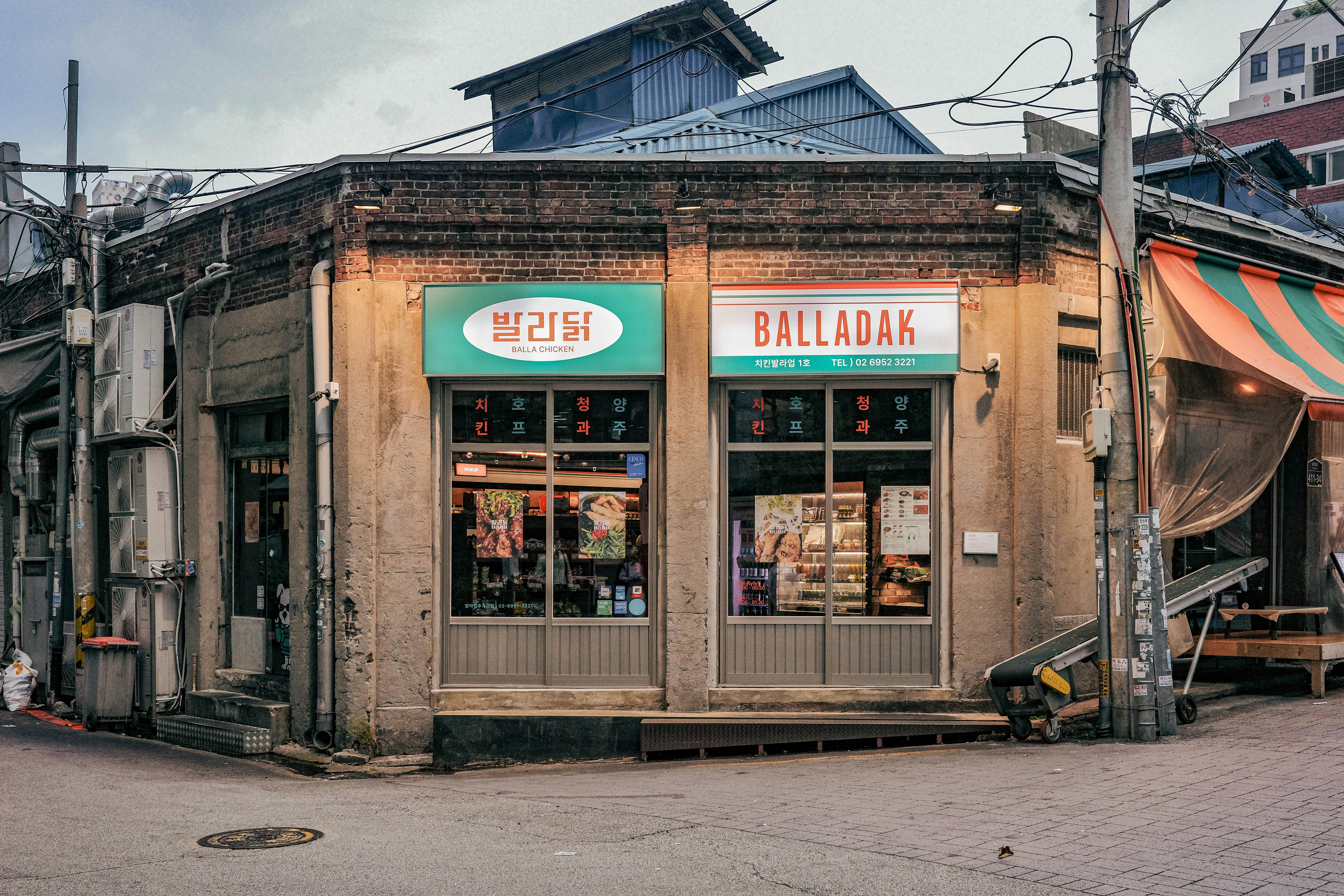 Teal Signage on a Weathered Brick Corner: Balladak Storefront