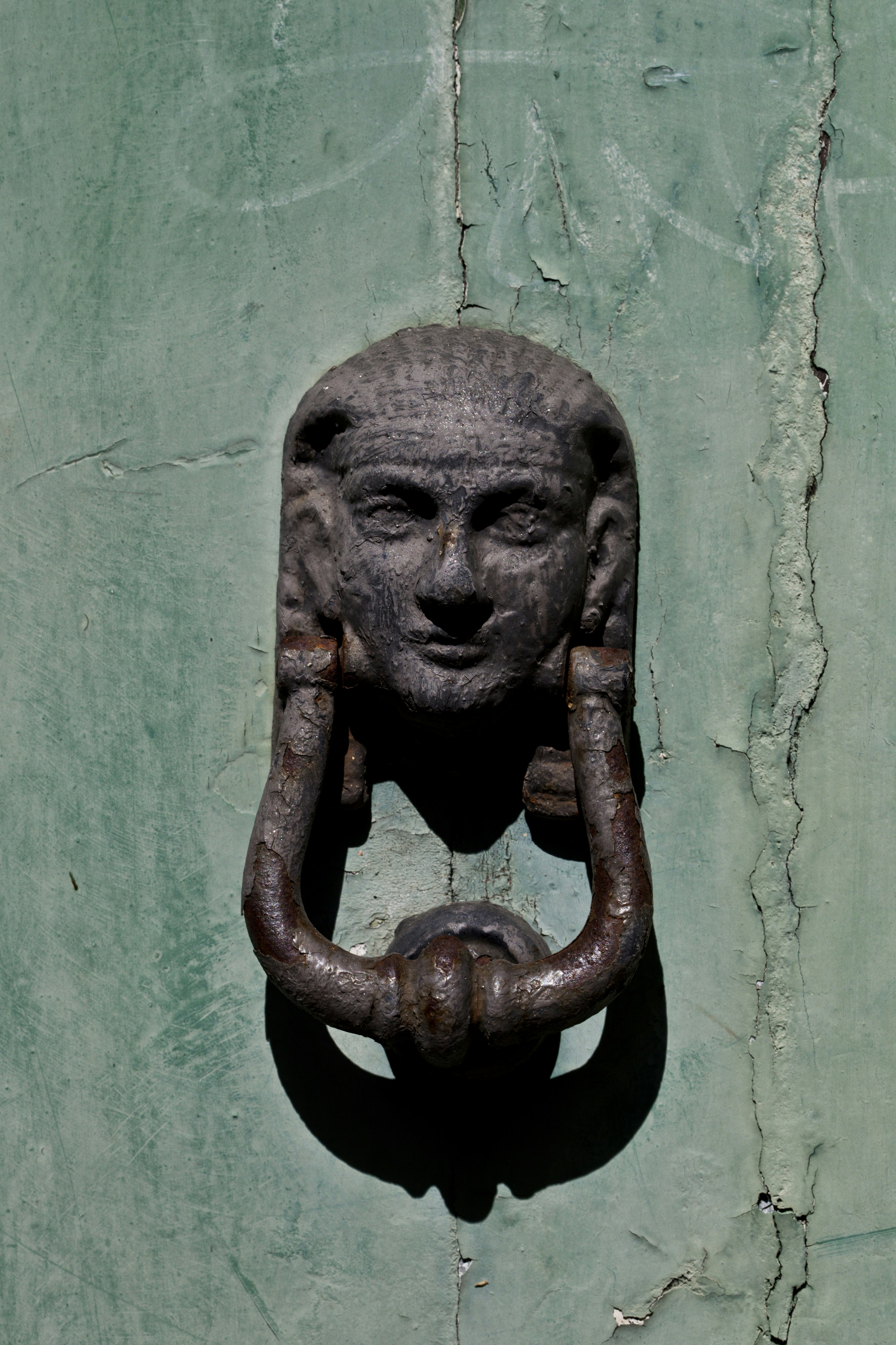 Iron Visage on a Cracked Green Door