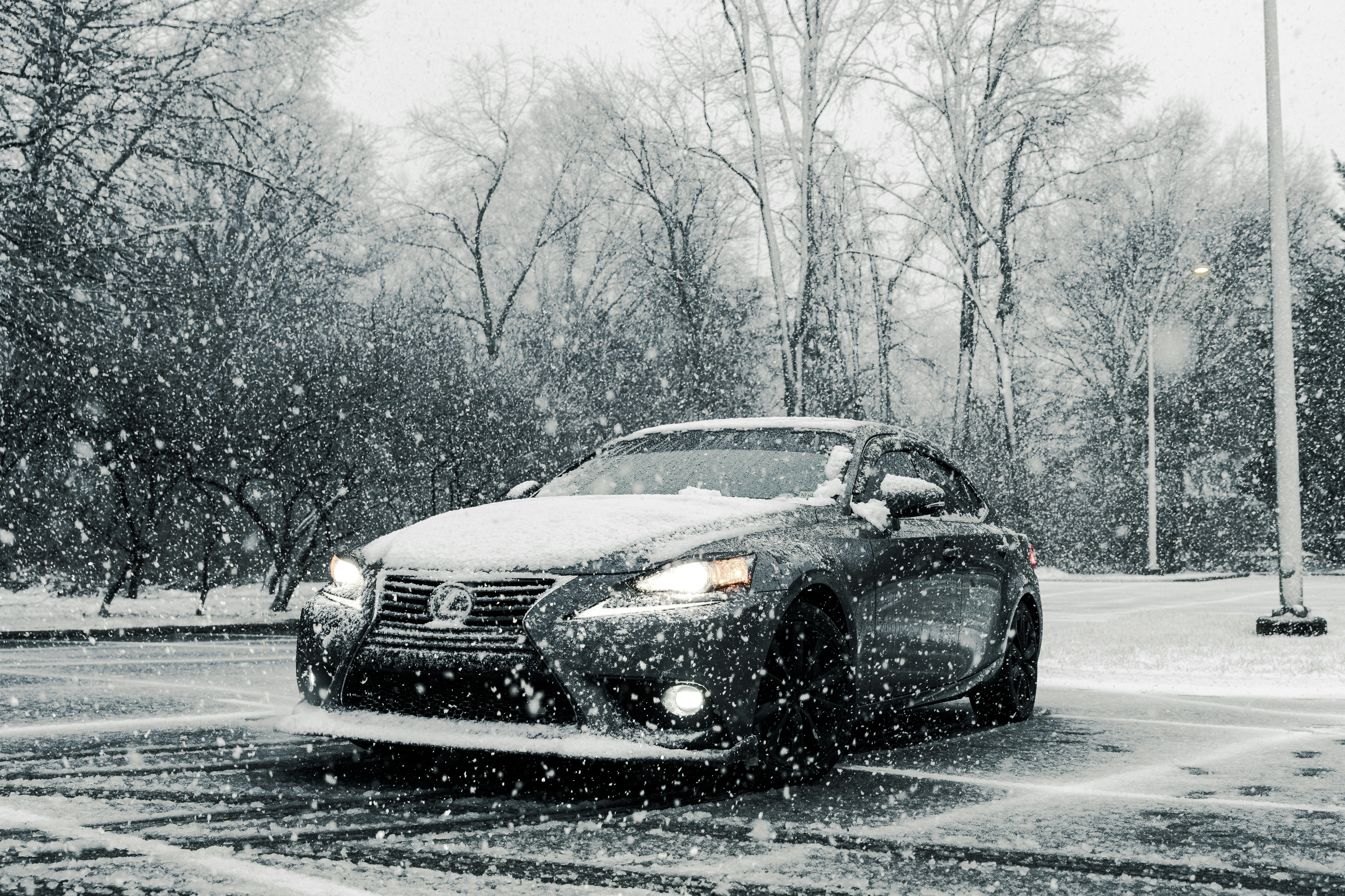 Front-Edge in a Snowstorm: A Dark Sedan Navigates a Silent Parking Lot