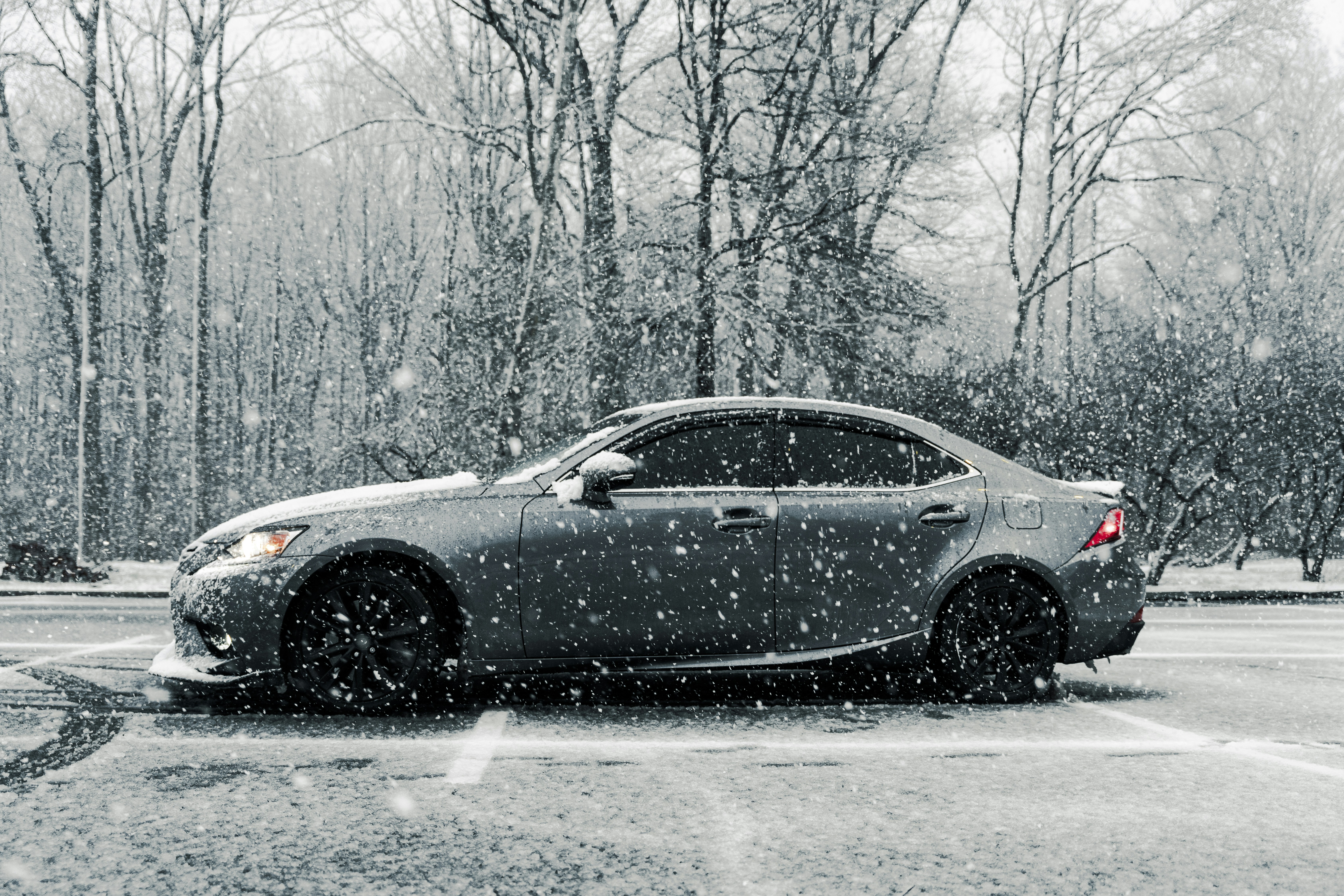 Midwinter Drift: A Silver Sedan Braced by Falling Snow in a Quiet Lot