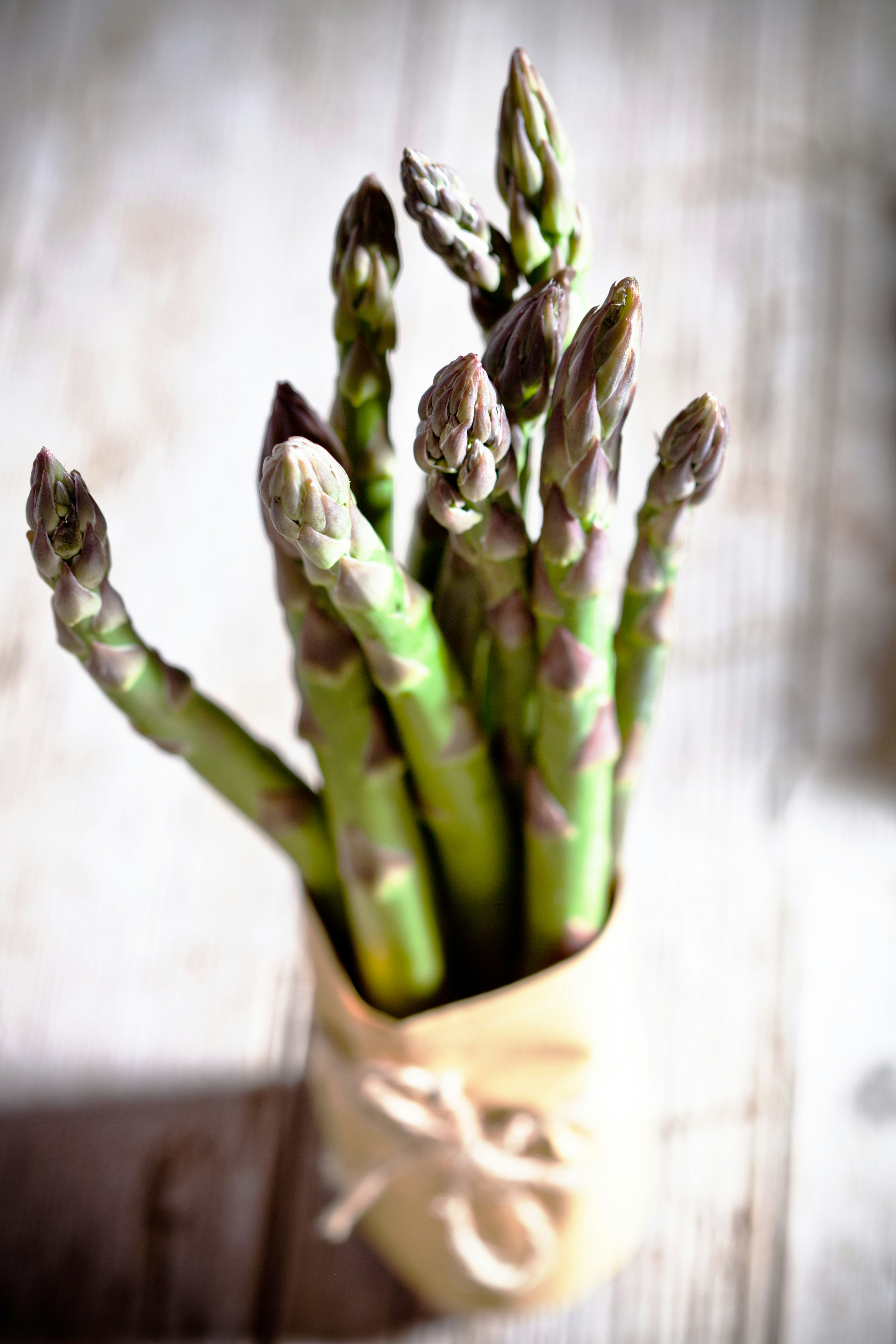 Morning-light asparagus bouquet bound with twine on a weathered wooden table