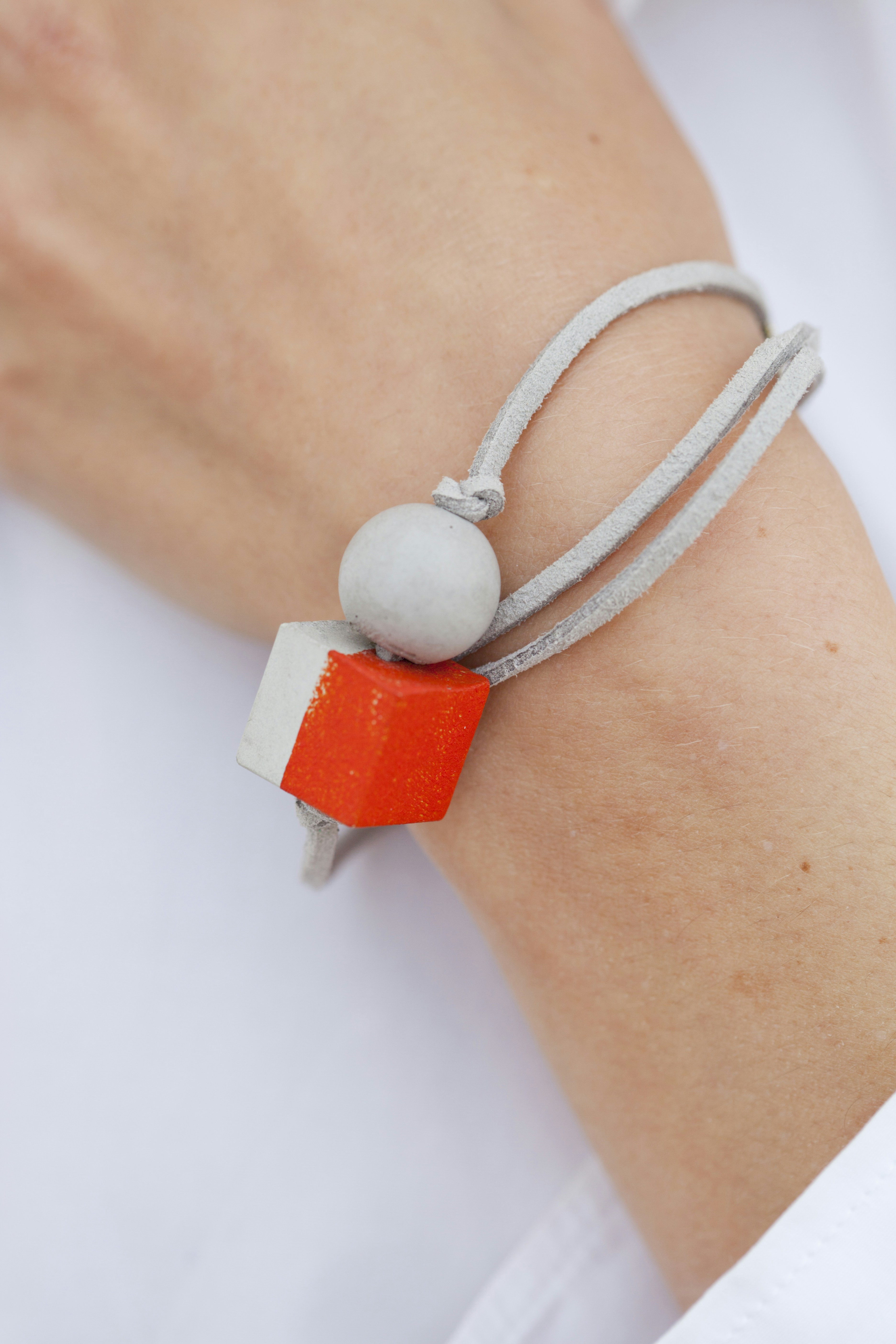 Bracelet Charm on a Bare Arm: Geometric Orange and Gray in Soft Light