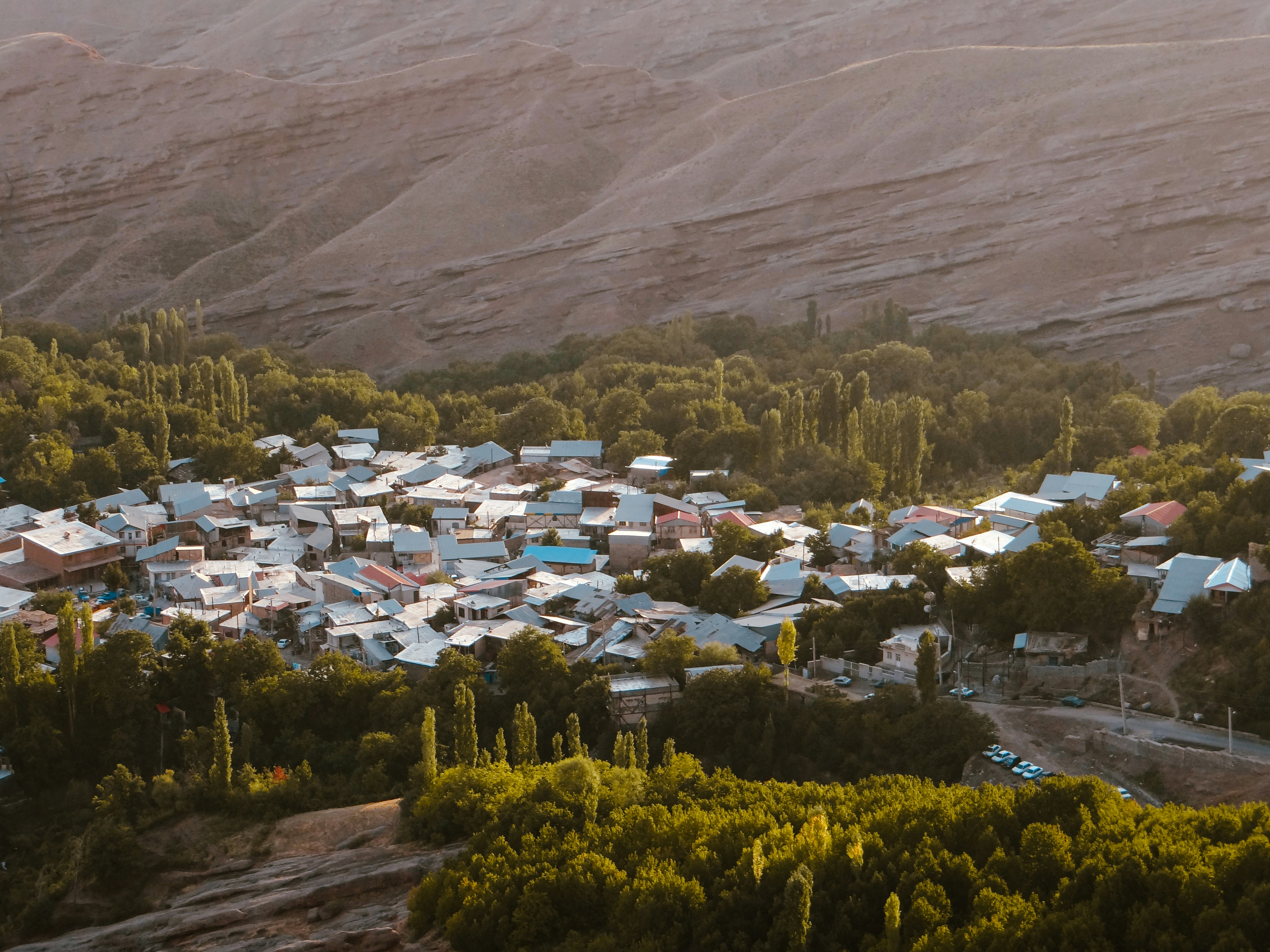 Ridgeside Mosaic: Colorful rooftops weave through a sunlit valley beneath arid slopes