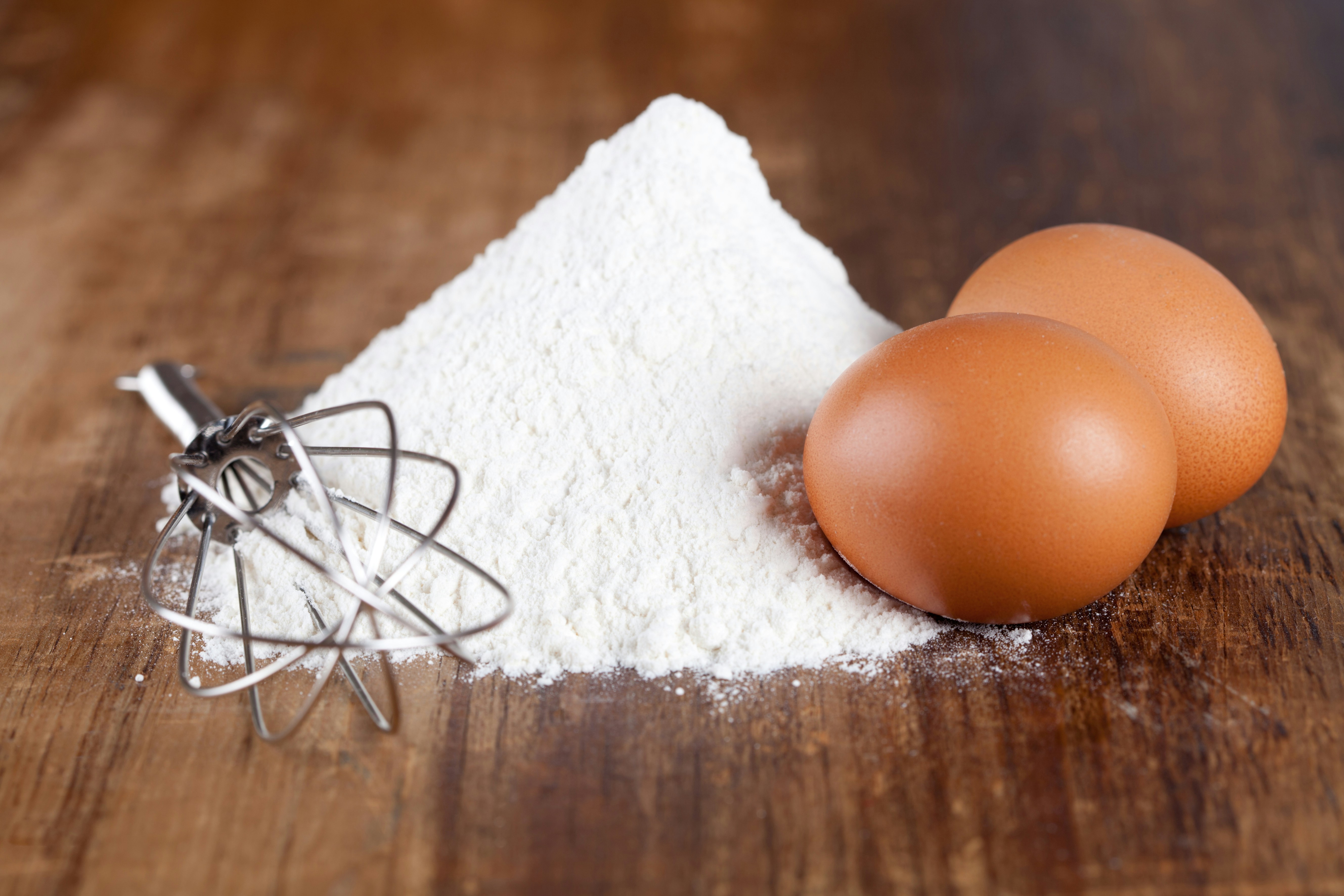 Pile of flour with eggs and whisk ready for baking
