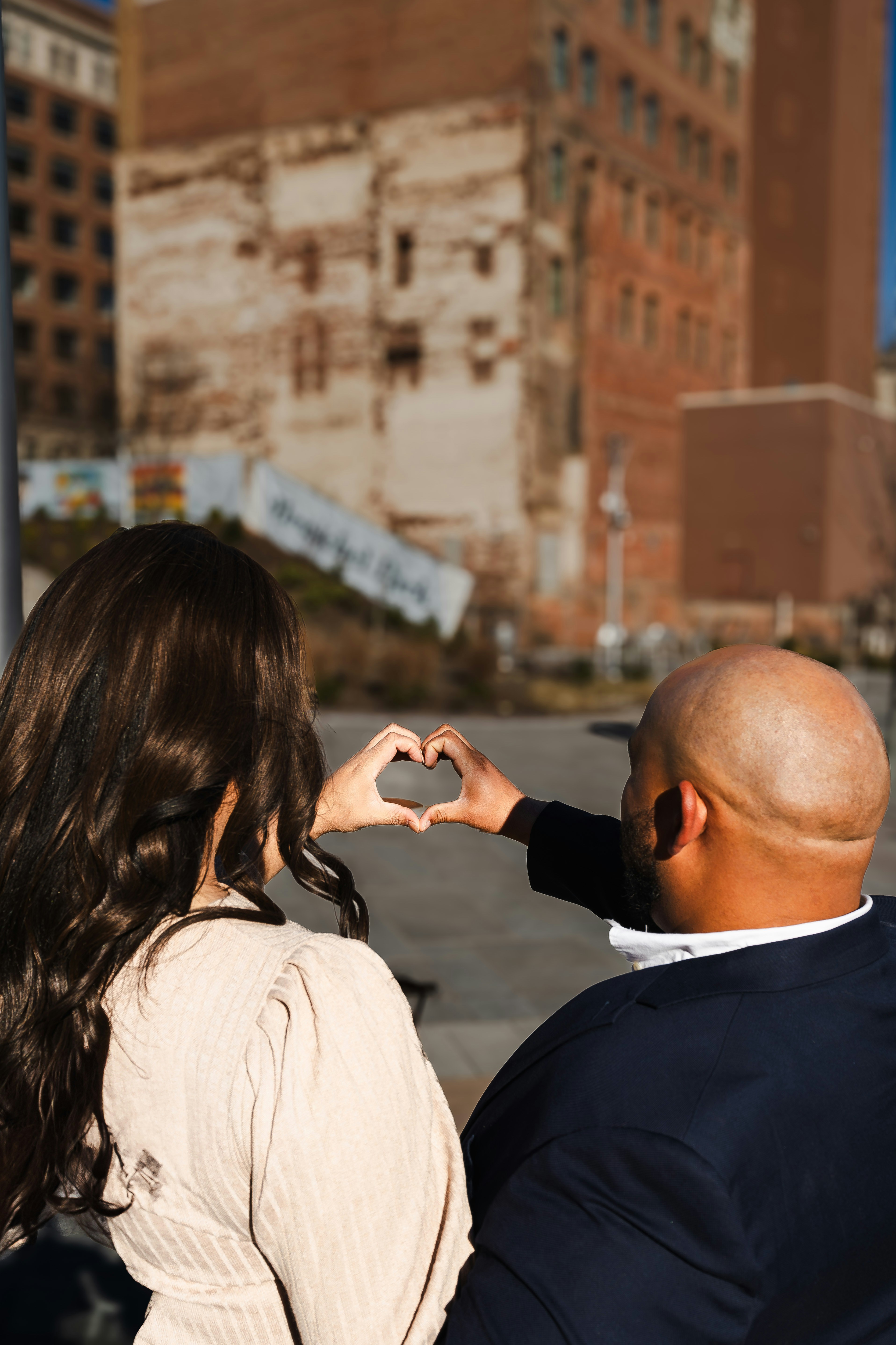 Urban Heartbeat: Hands Form a Love Gesture in Front of Weathered Brick