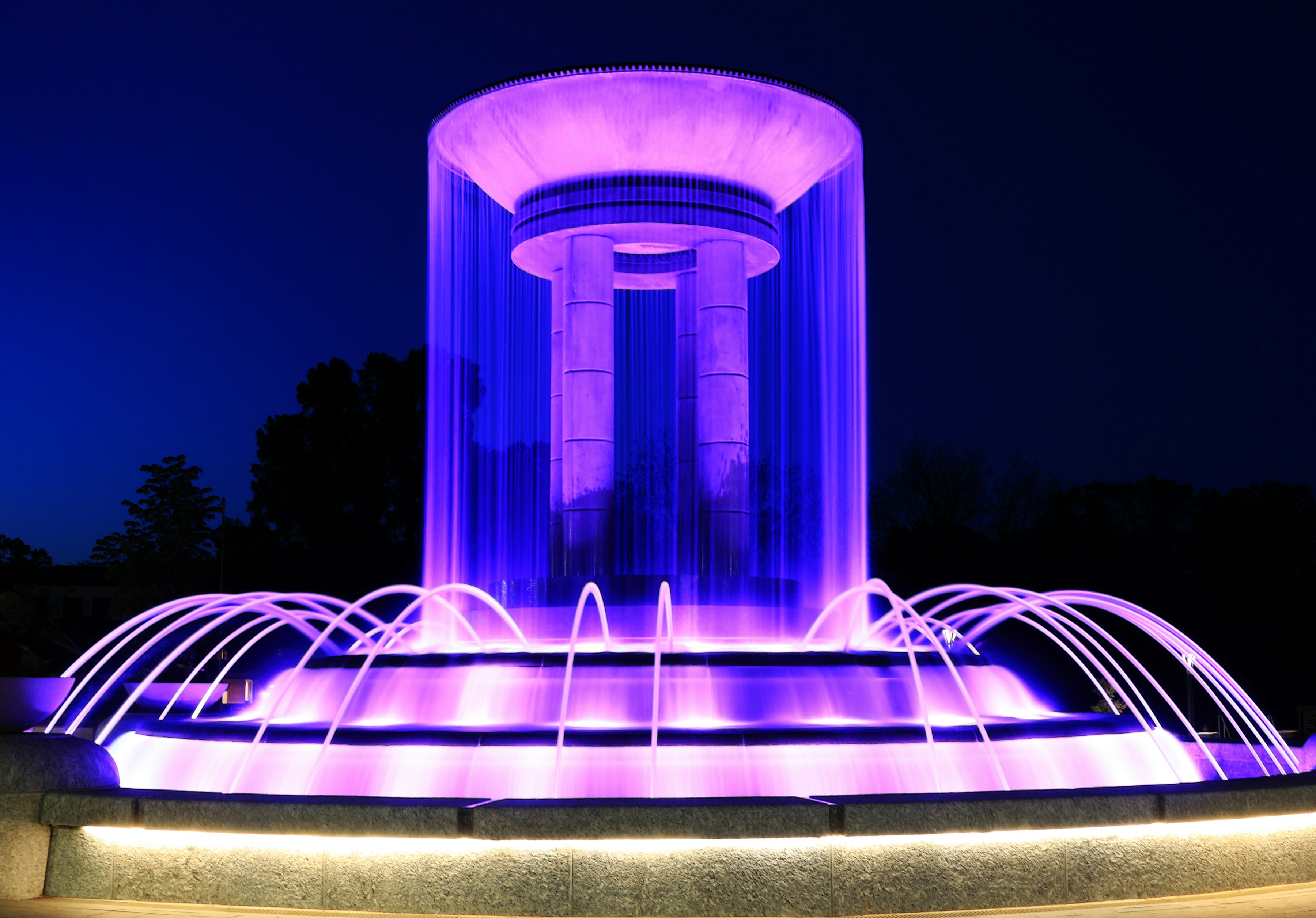 A water fountain lit up with purple lights photo – Free Cary Image on ...