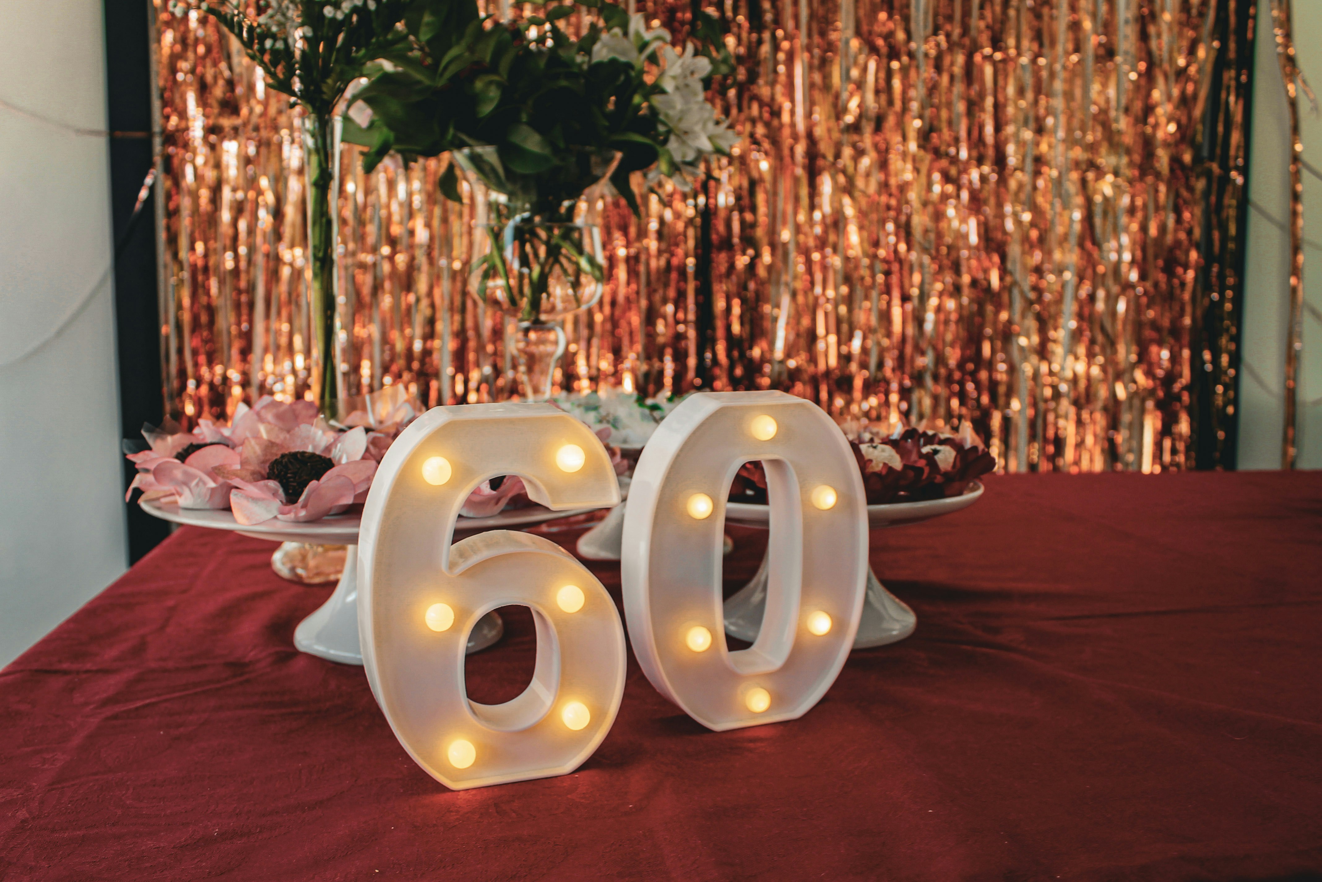 Illuminated number 60 on a red tablecloth with a shimmering copper backdrop.