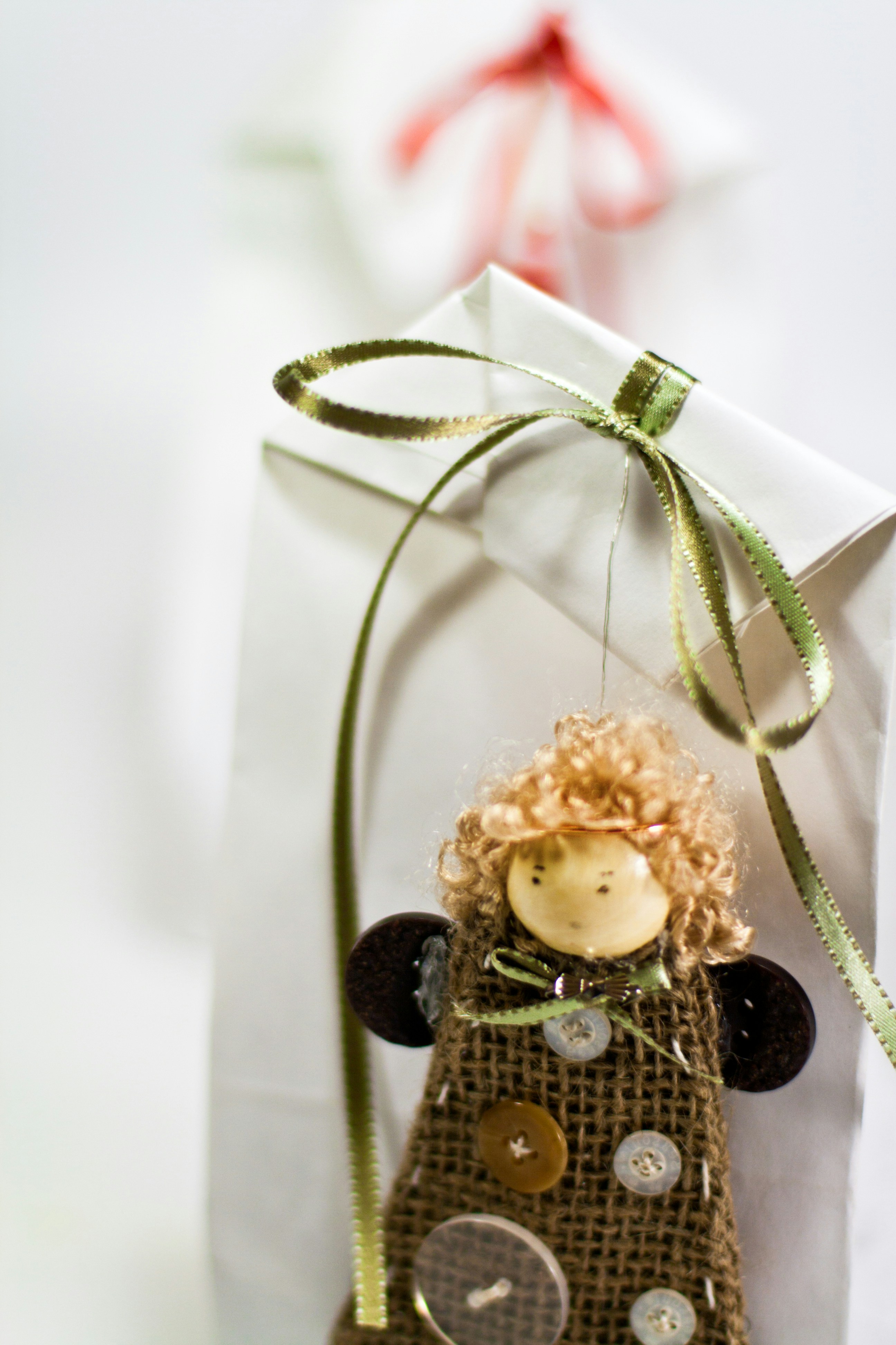 Gift-wrapped Angel: a handcrafted charm rests beside a ribbon-wrapped box