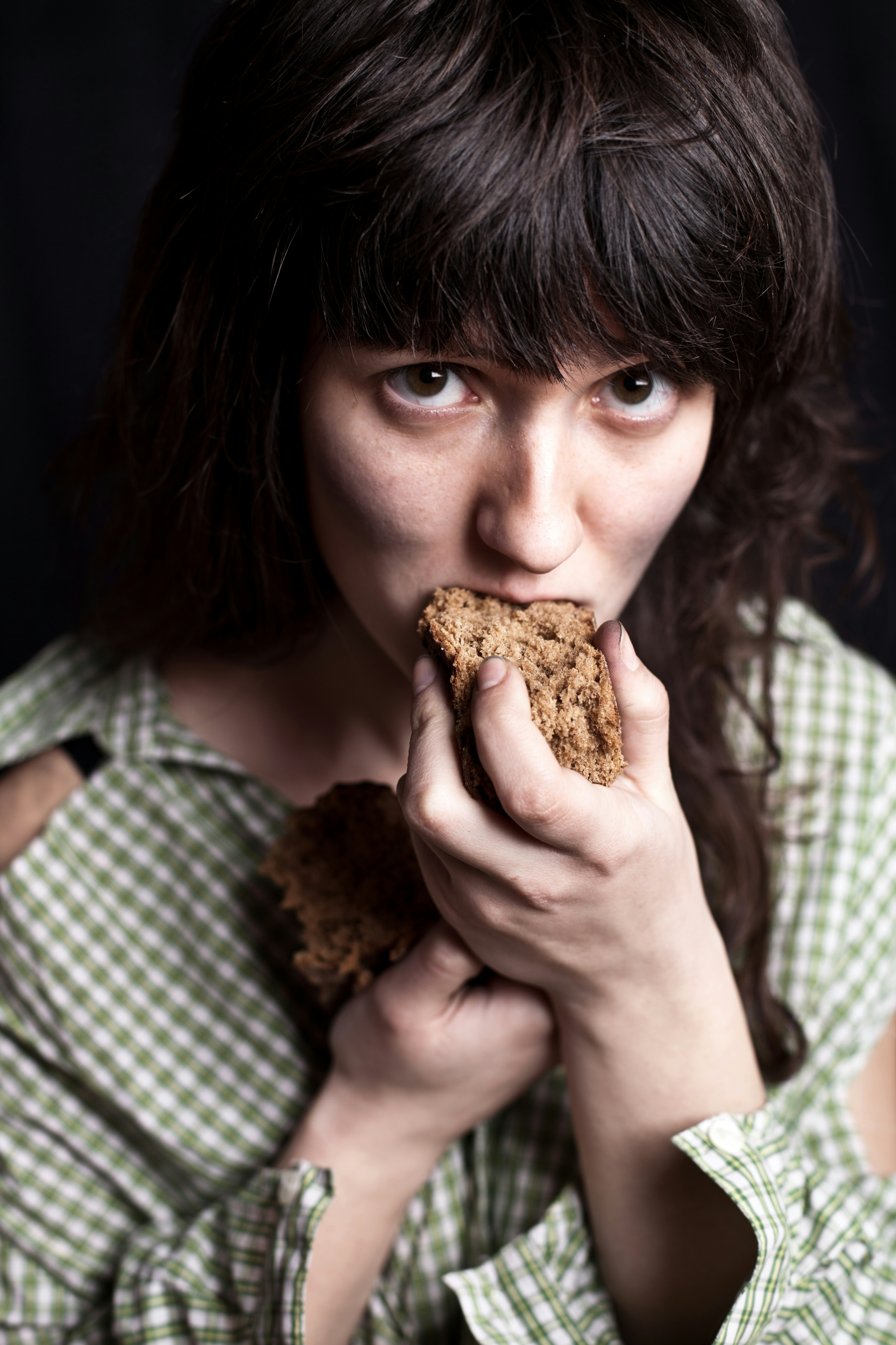 A woman eating a cookie while wearing a green and white shirt photo ...