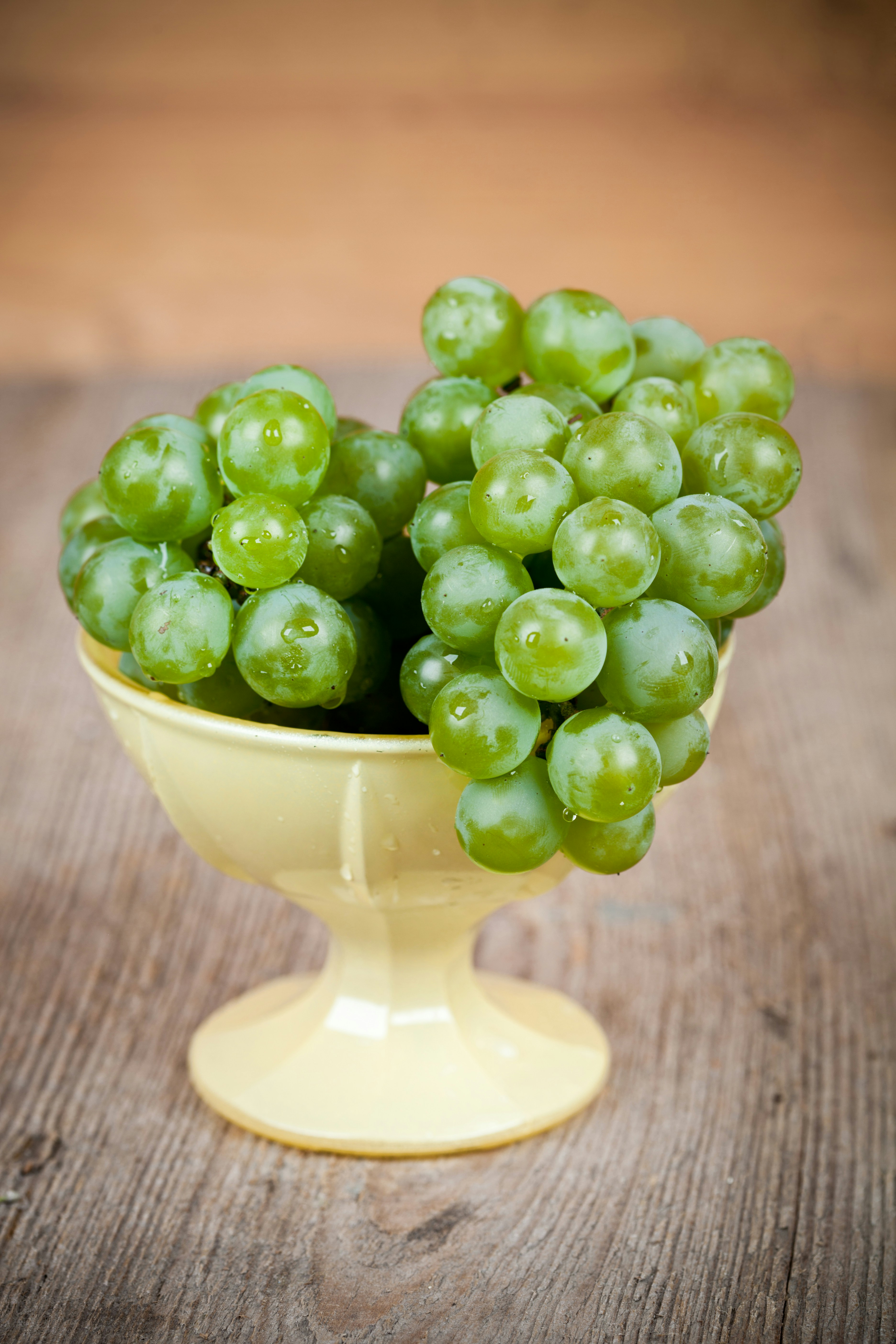 Emerald Cluster on a Cream Pedestal: Grapes Against Weathered Wood