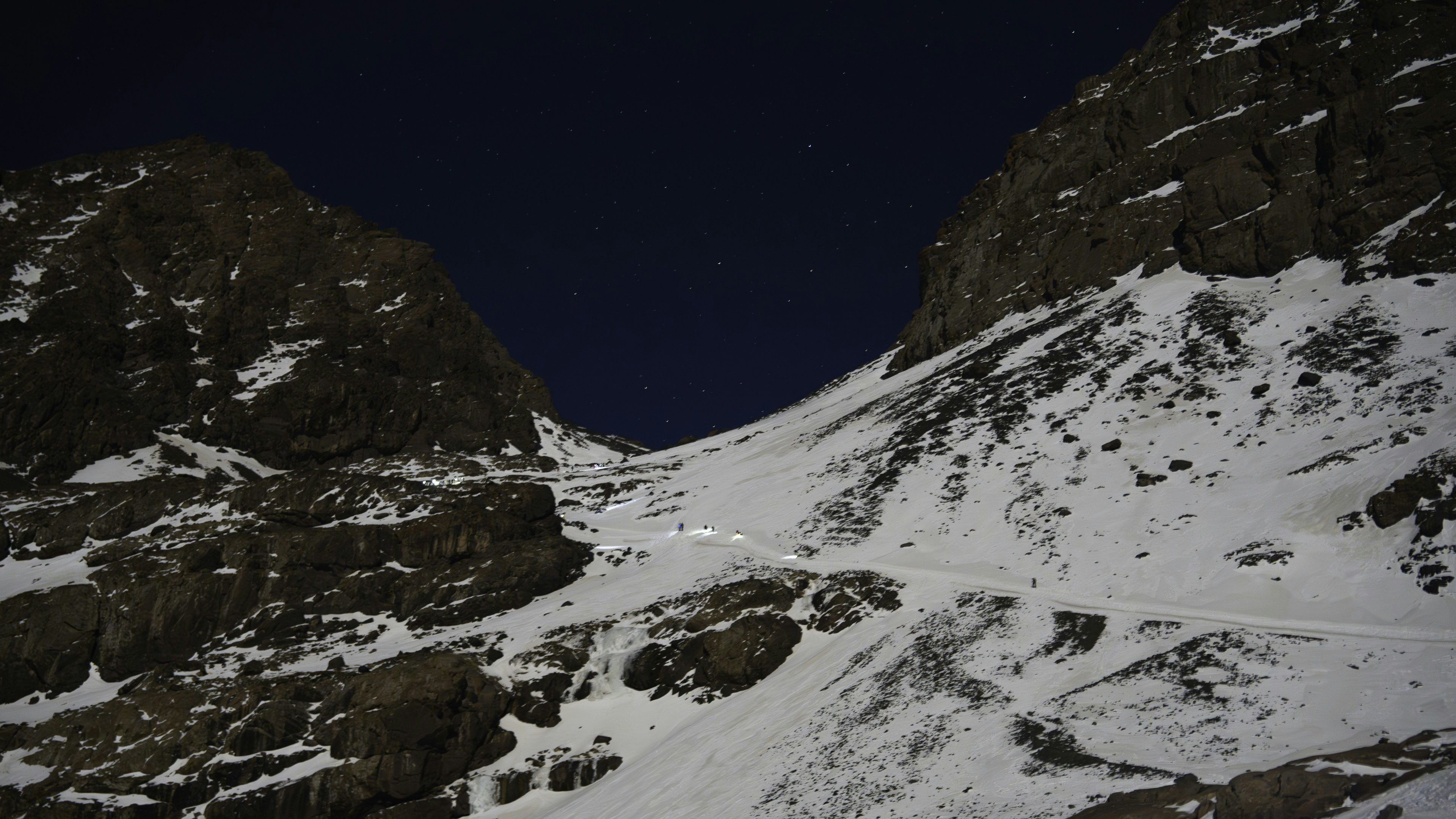 Starry Alpine Gorge: Snow-lit Trail Between Dark Cliffs