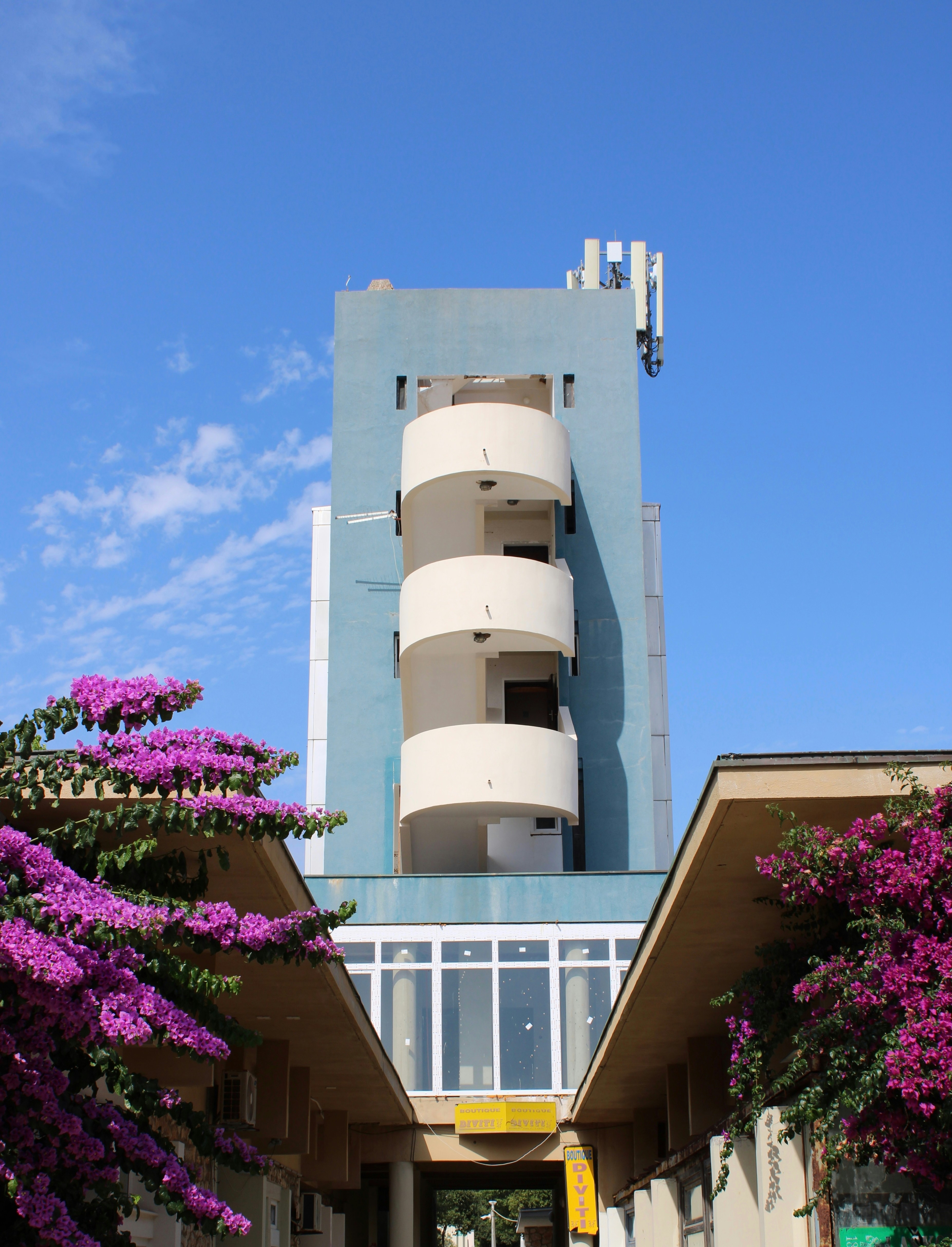 Cascading Cylinders: A Blue Tower Rising Between Bougainvillea