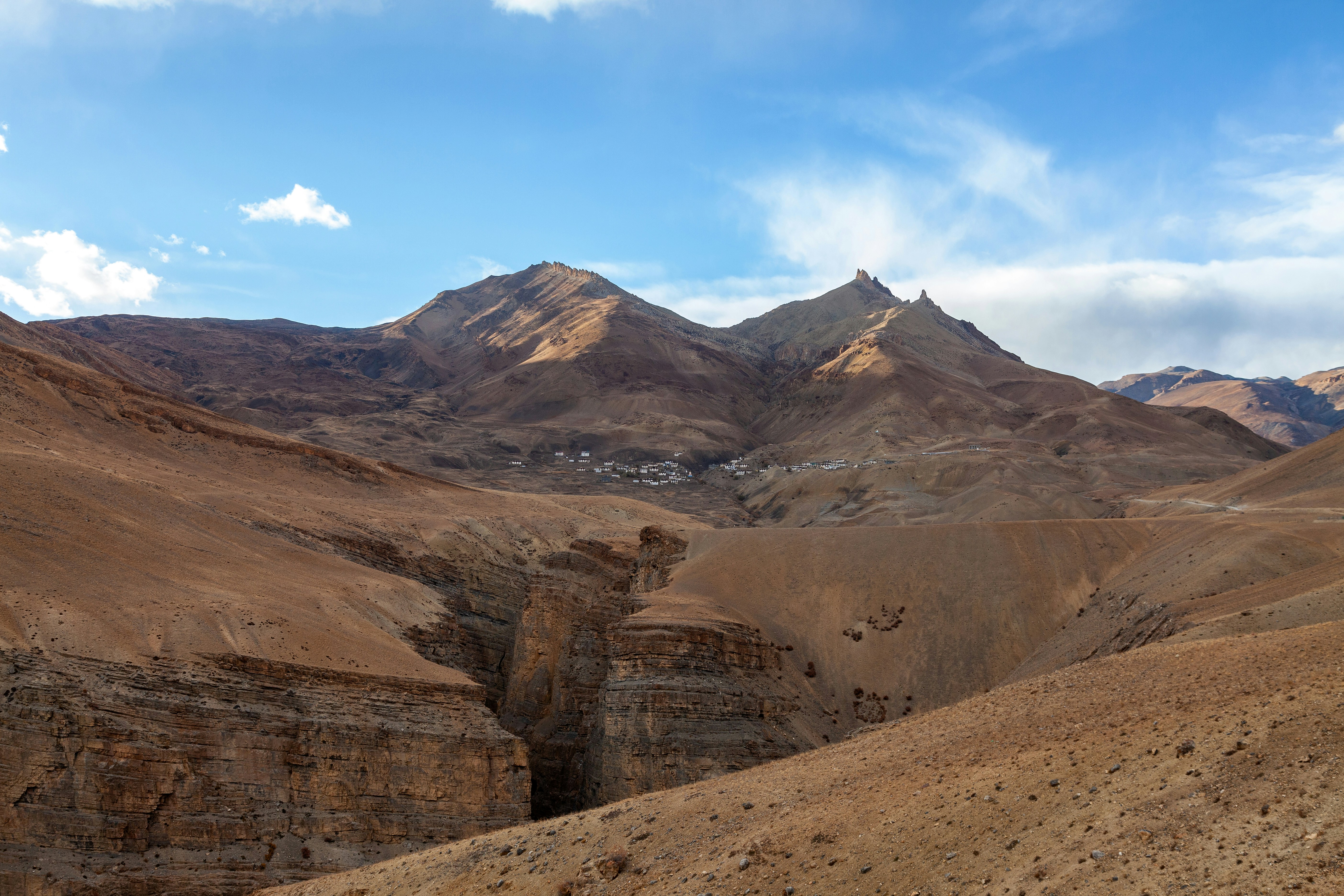 Mountainous desert terrain with rugged cliffs under a vibrant blue sky.