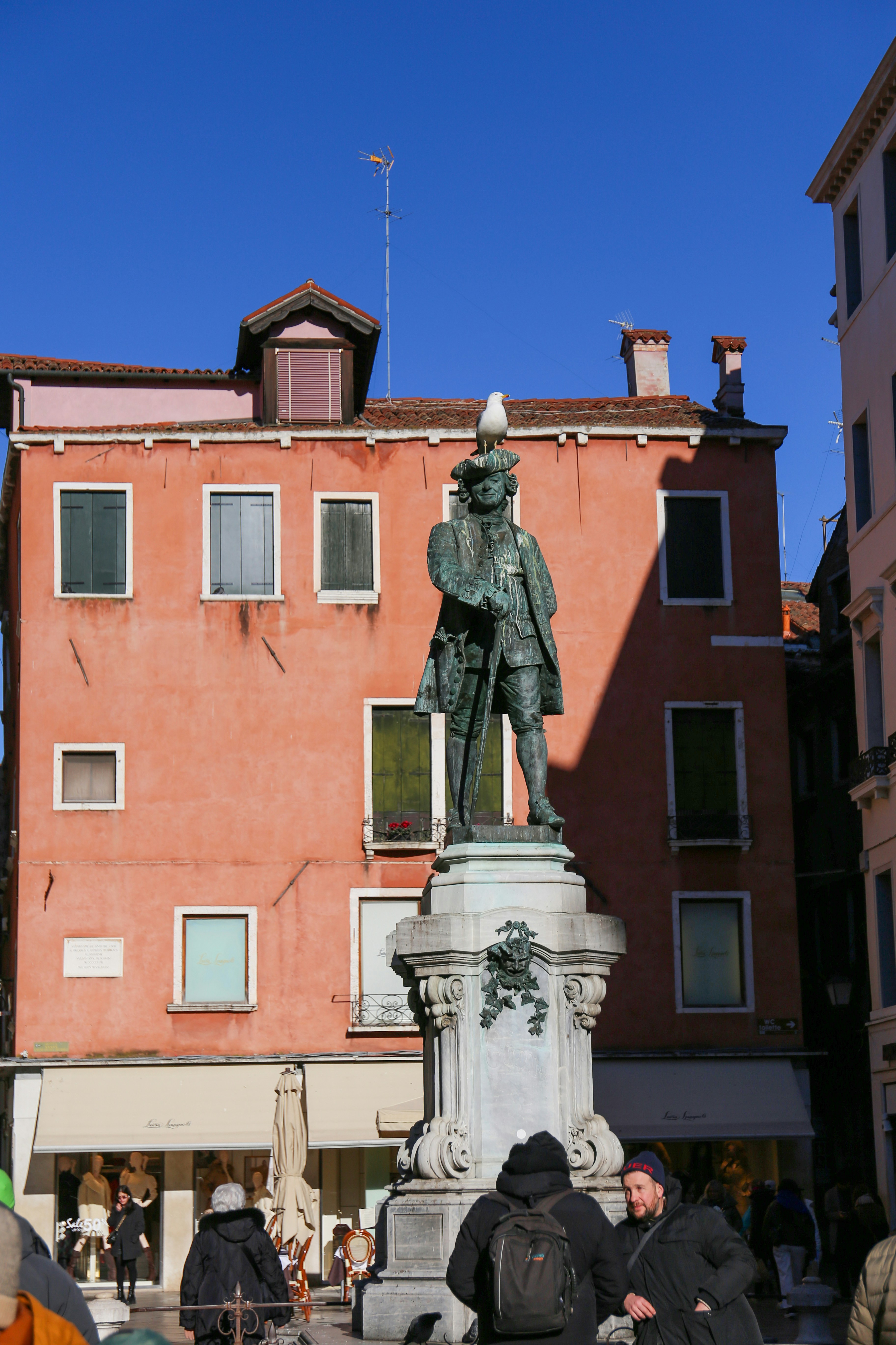 Seagull Sentinel: Bronze Statue Framed by Sunlit Terracotta Facades