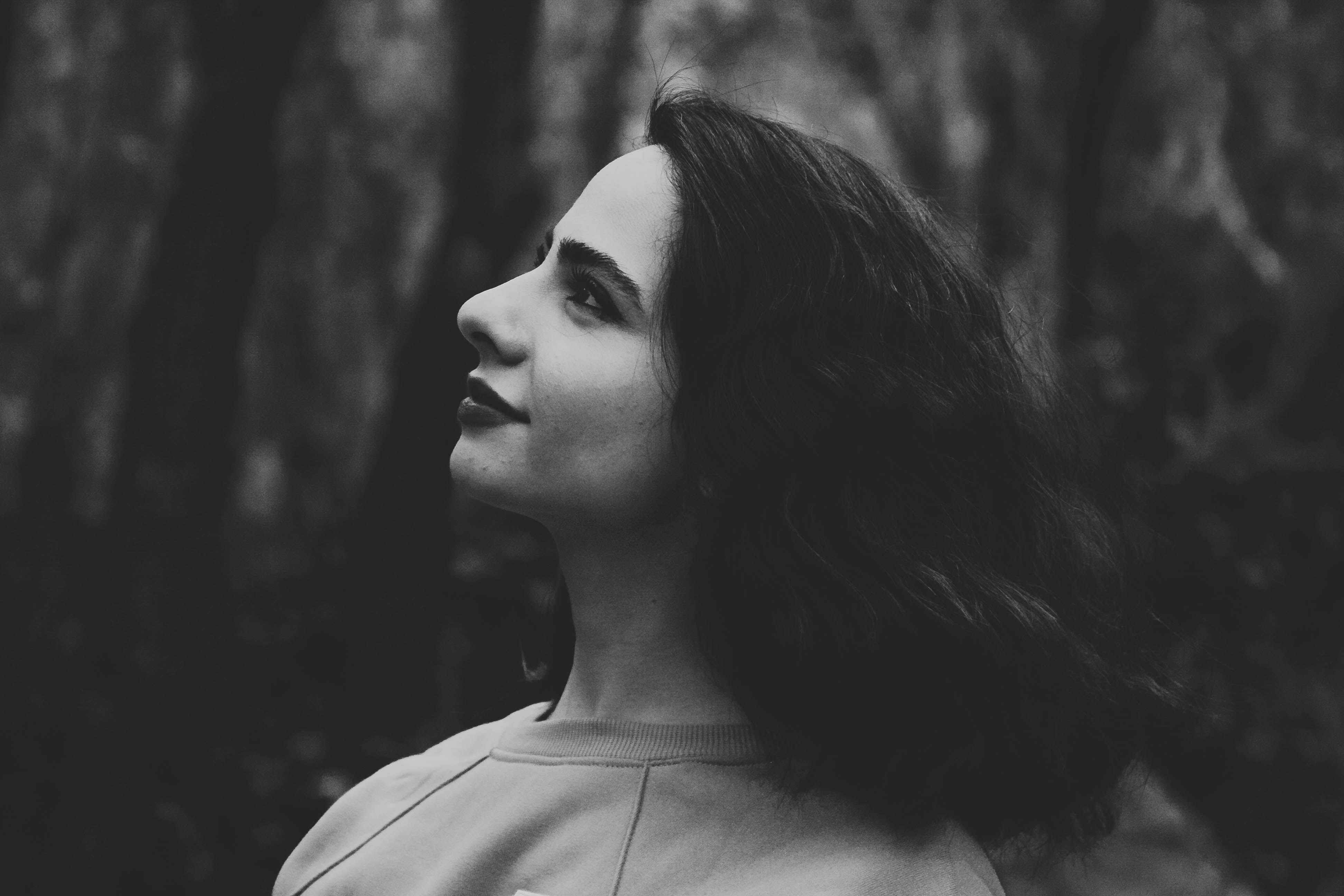 Profile of a woman looking upward against a blurred forest background.