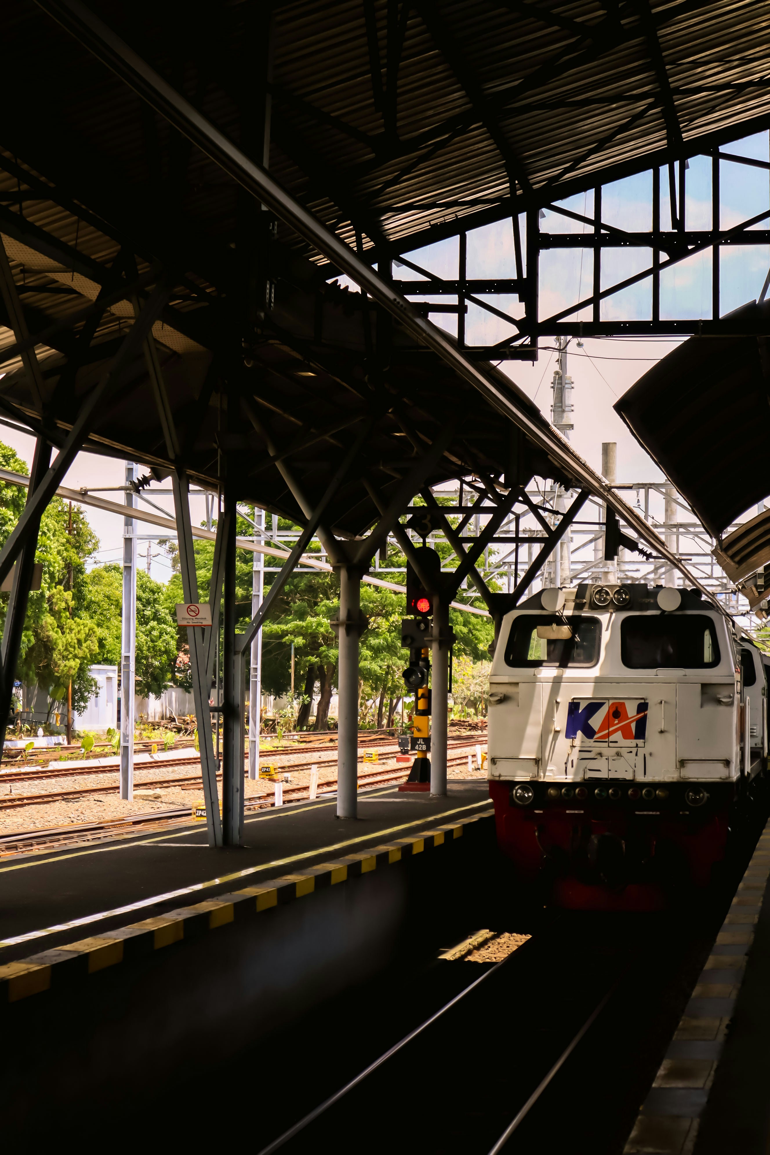 A white train traveling down train tracks next to a train station photo ...