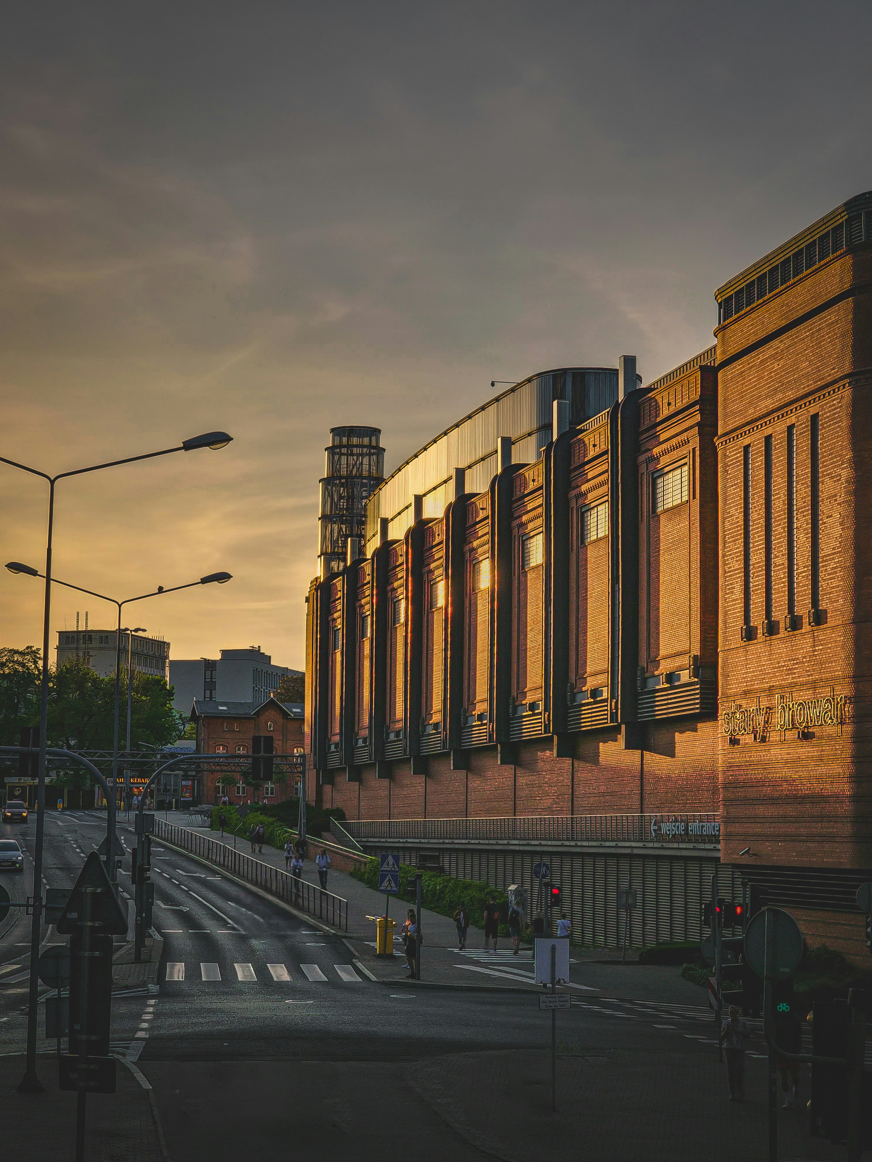 Sunset casts warm light on a historic brick building by a quiet street.