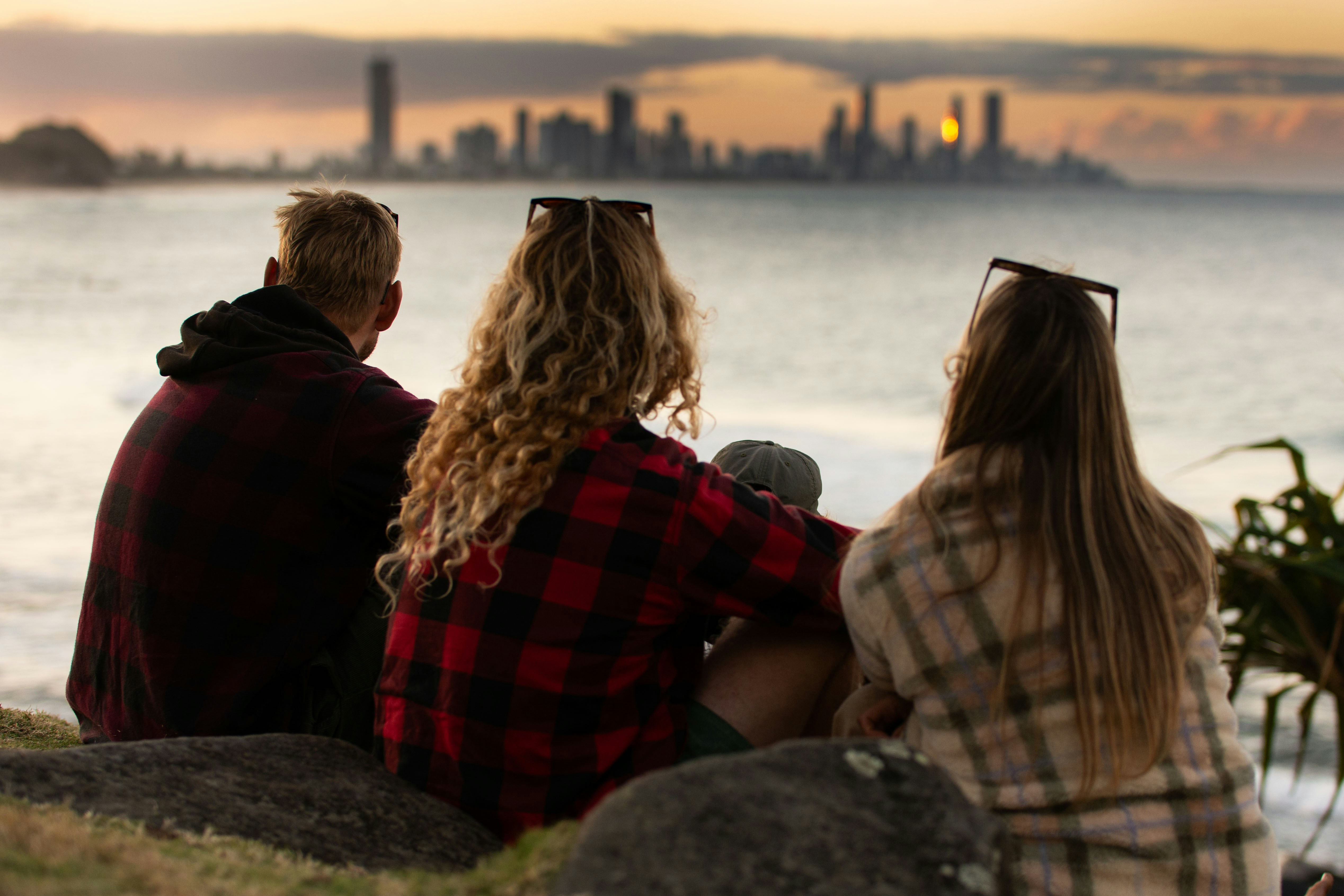 Sunset by the Water: Friends Watch the Skyline from the Rocks