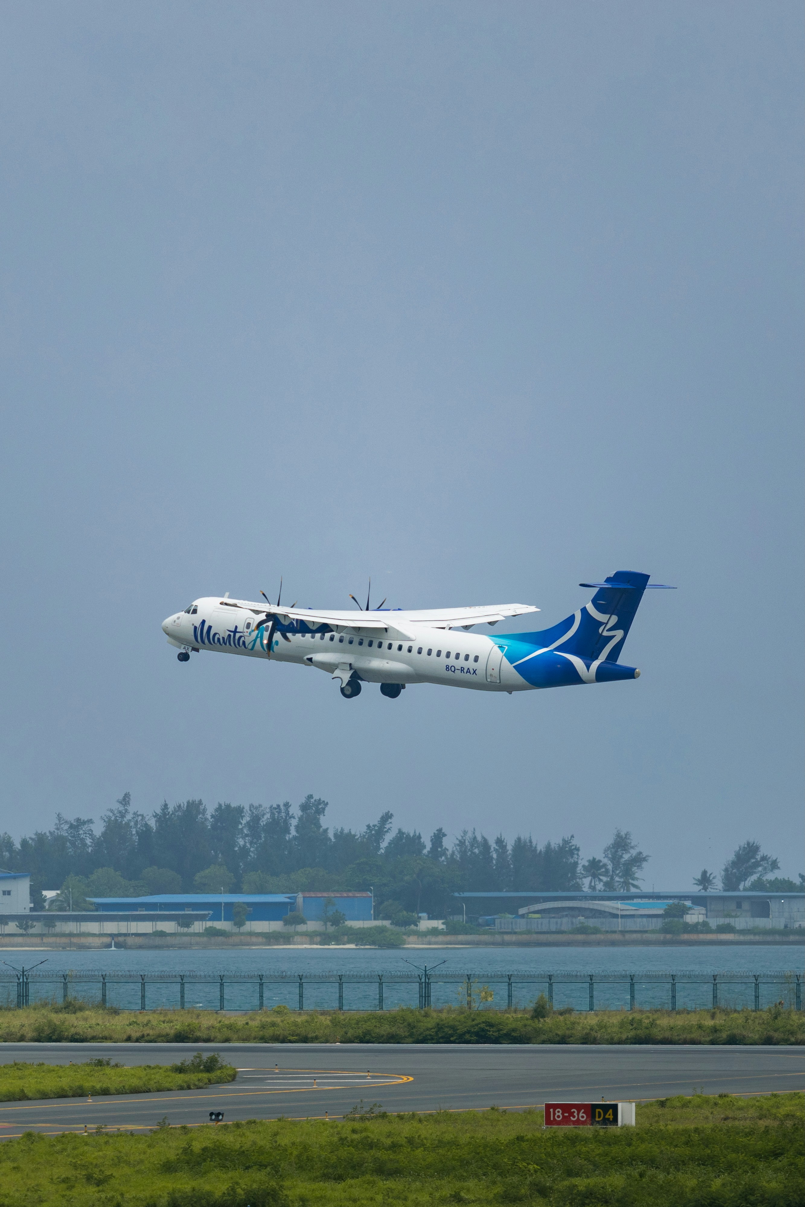 Blue-liveried Dash 8 lifts off over a quiet coastal airfield