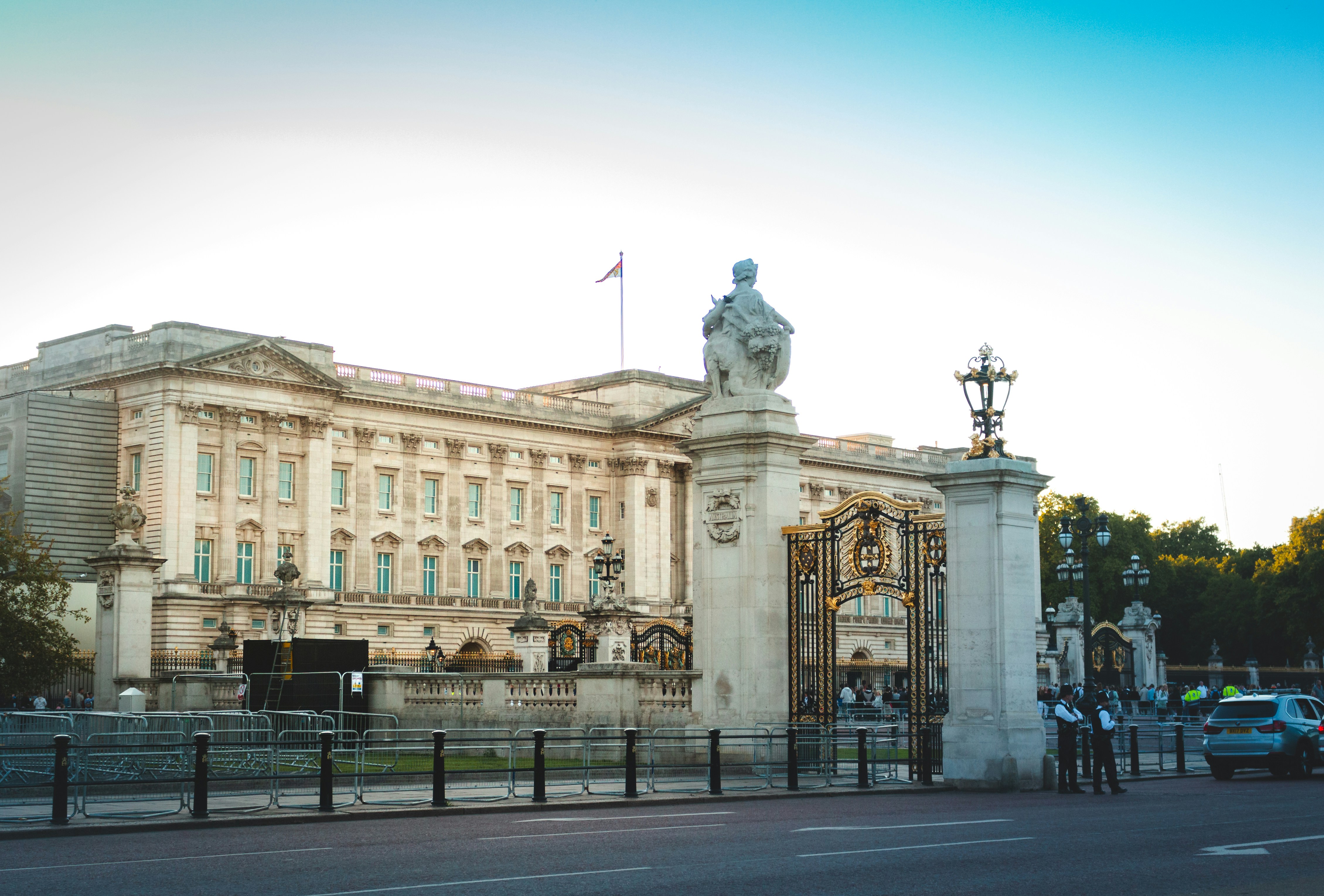 Ornate gates and statues frame a grand palace under a clear sky.