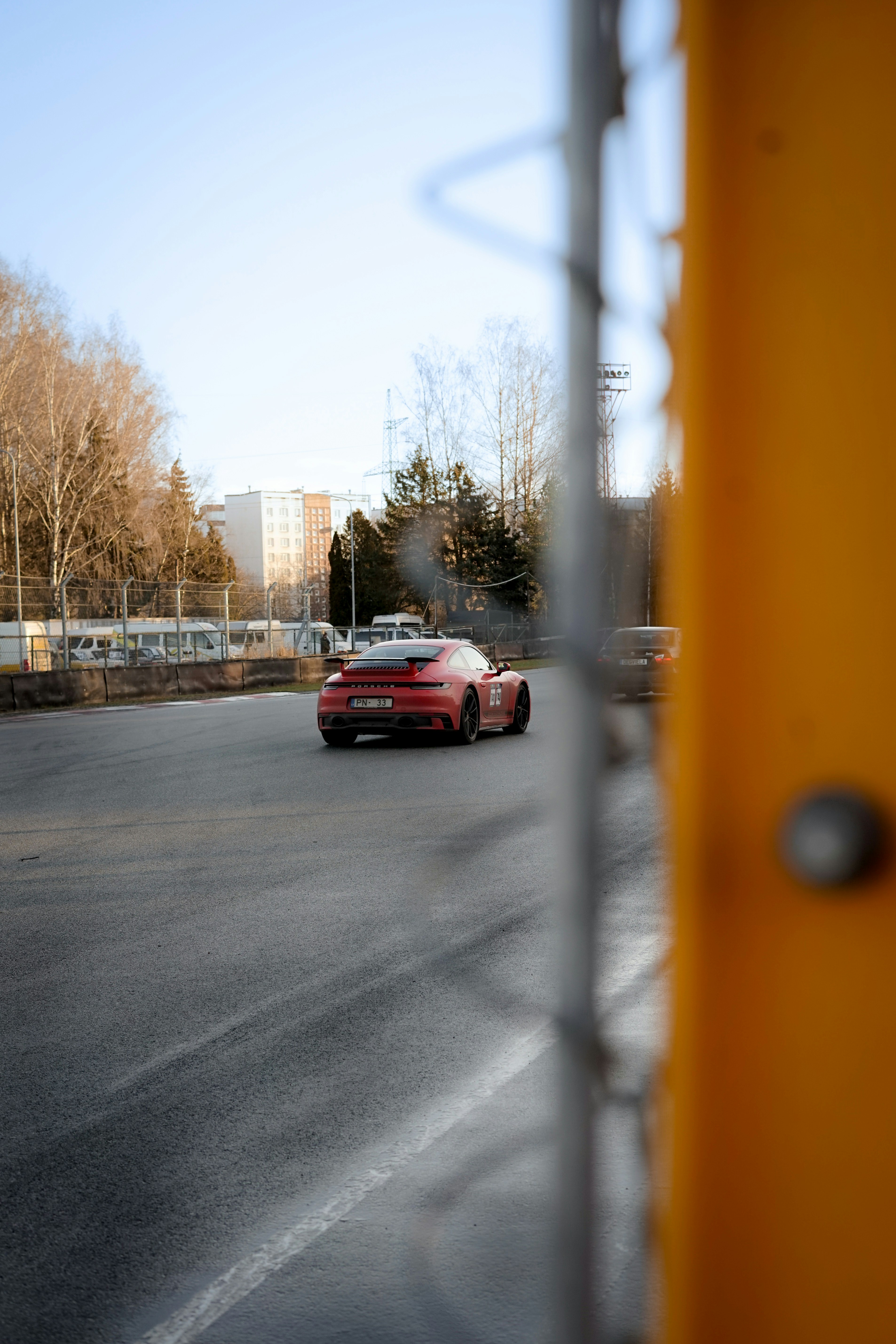 Red Sports Car on a Quiet City Street Framed by a Blurred Barrier