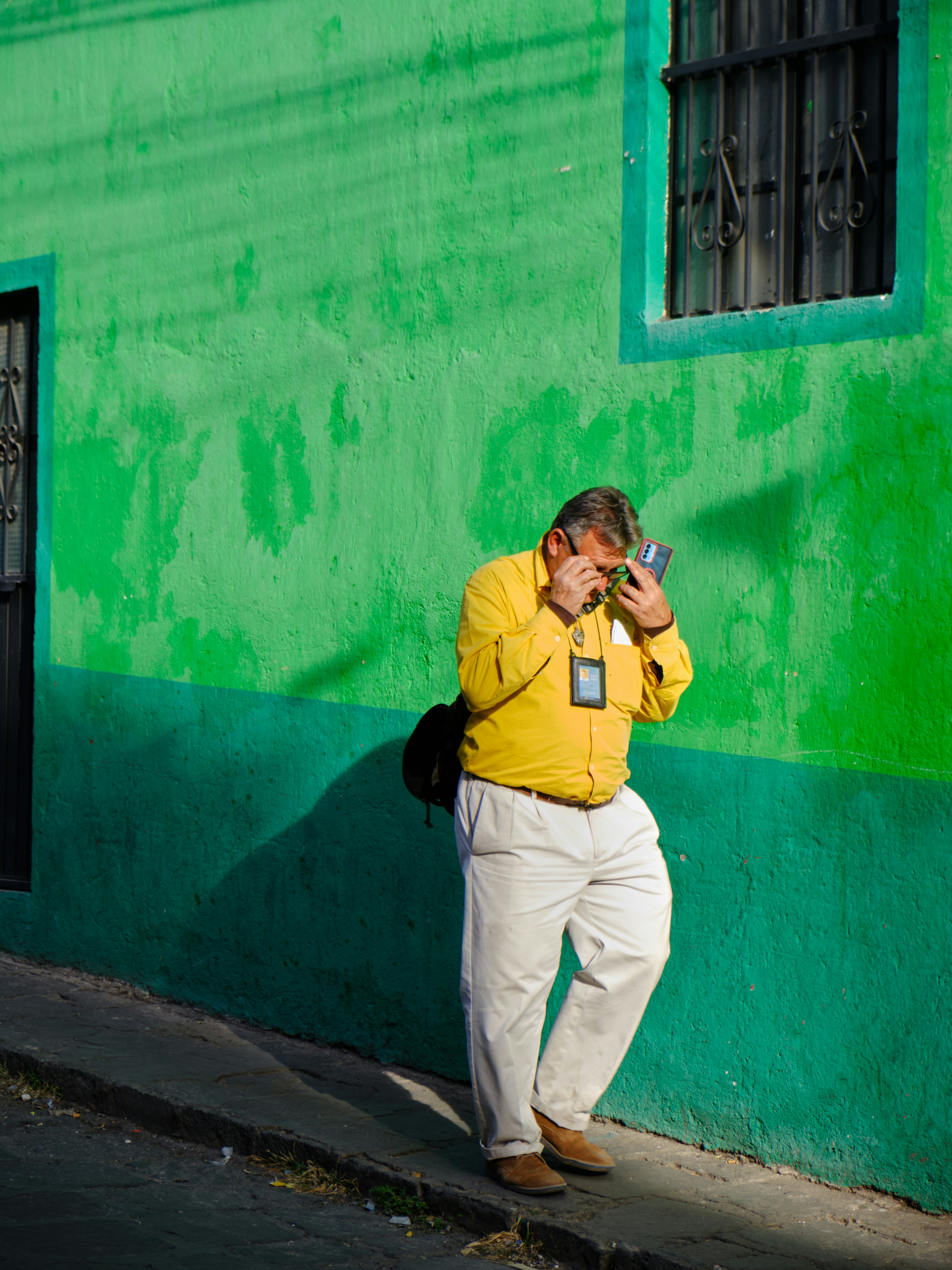 Yellow-shirted photographer against a vivid green wall