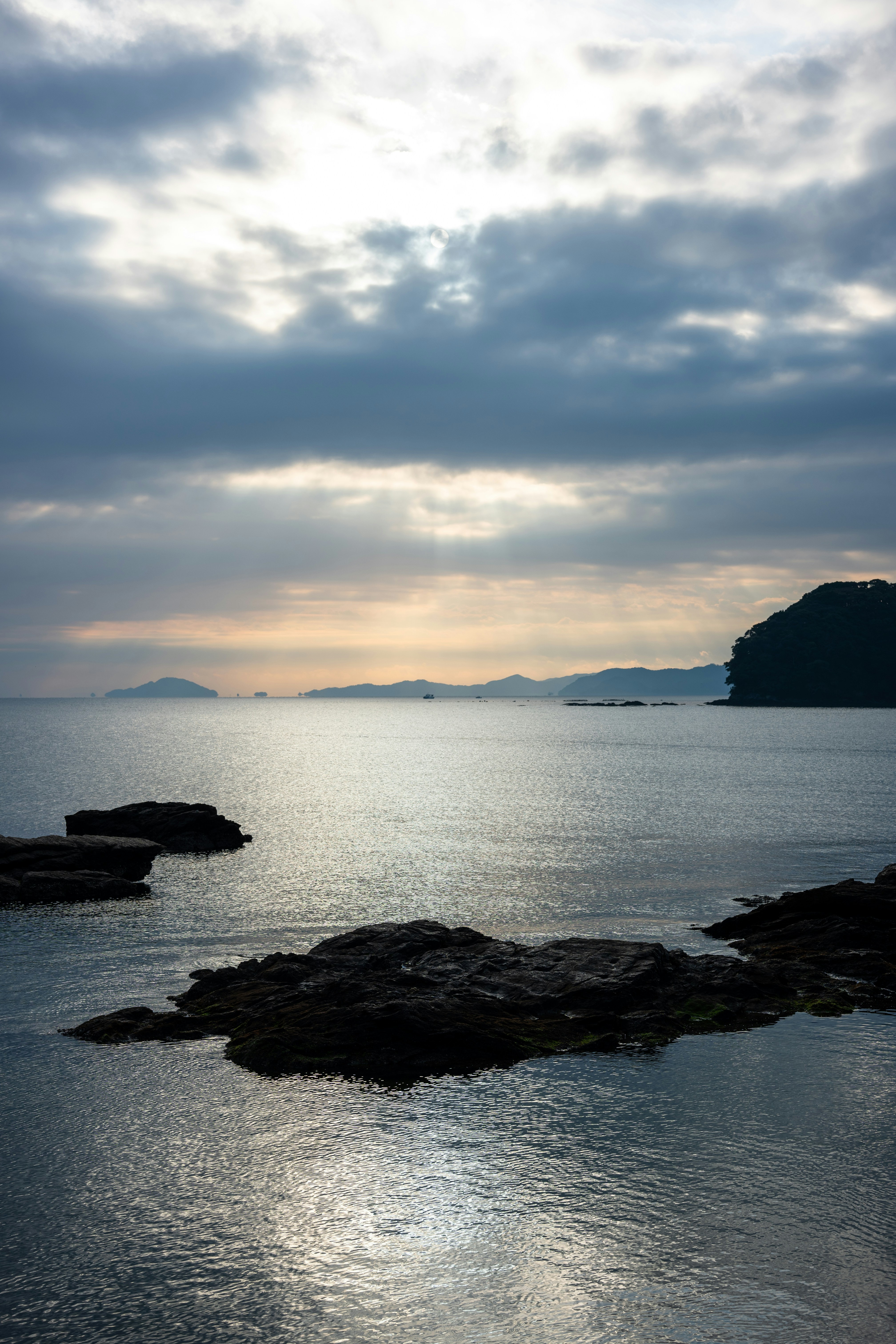 A body of water surrounded by rocks under a cloudy sky photo – Free ...