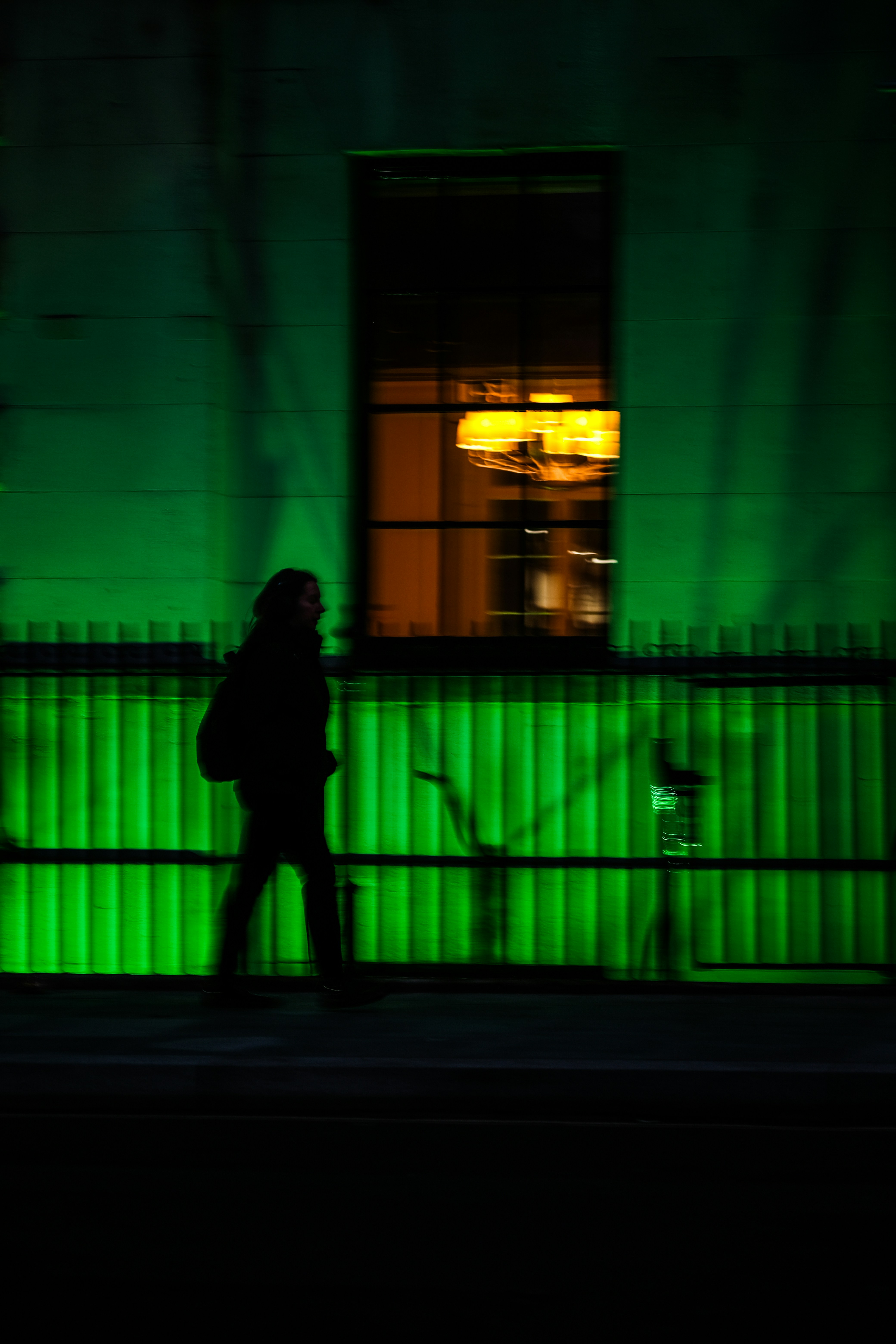 Green Hour: A One-Person Shadow Against a Neon Facade