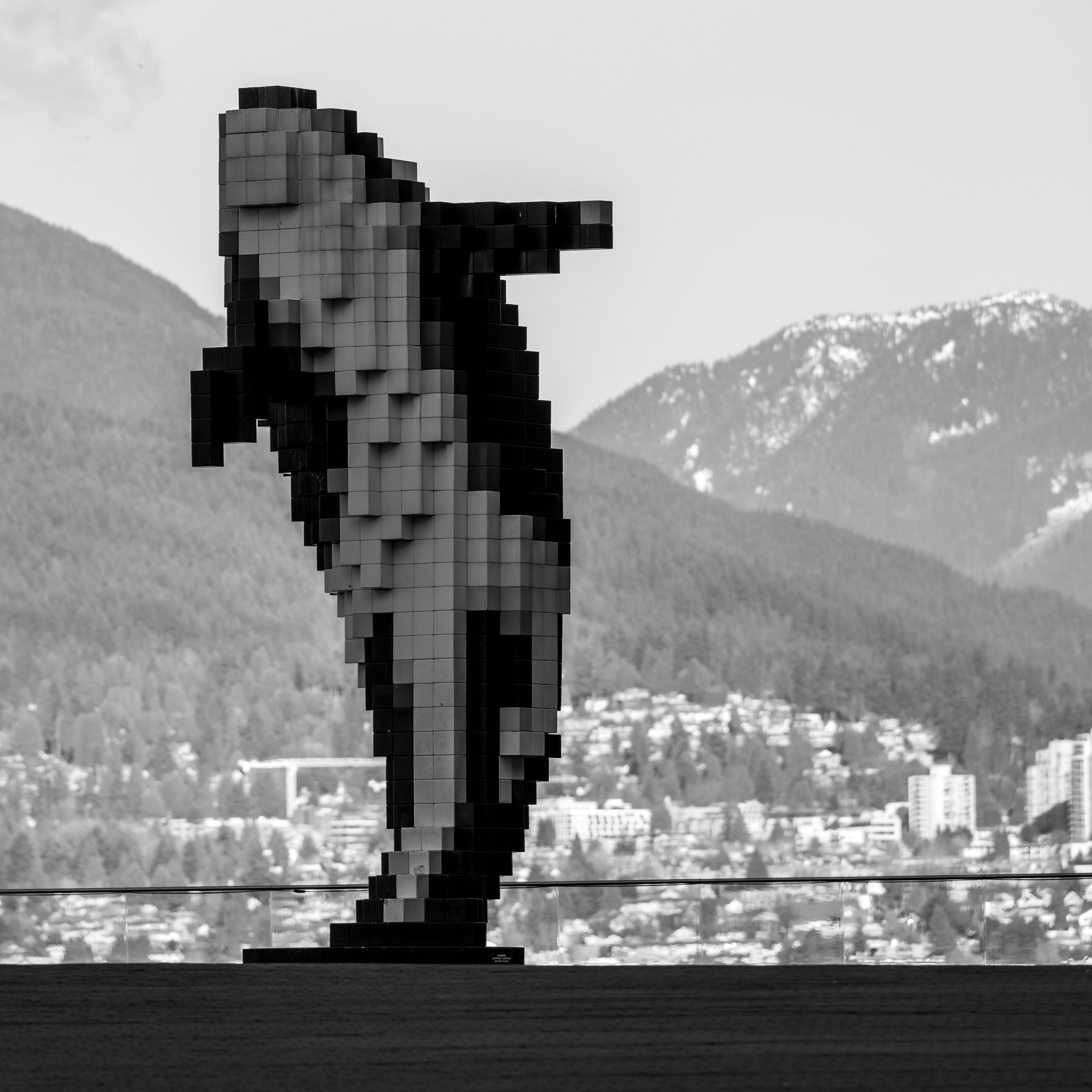 A black and white photo of a person standing in front of a mountain