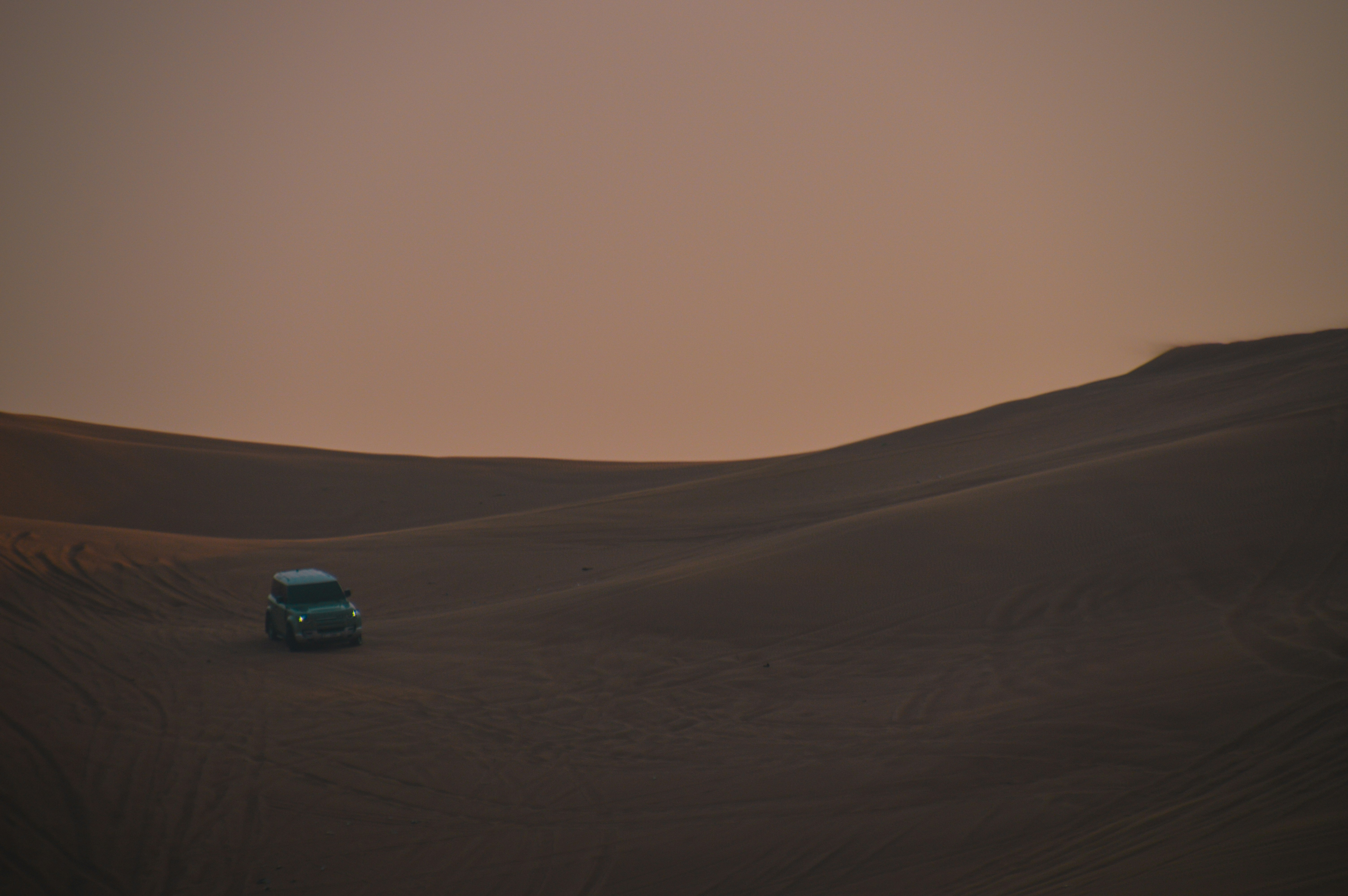 Lone SUV Carves a Quiet Path Across Dusky Desert Dunes