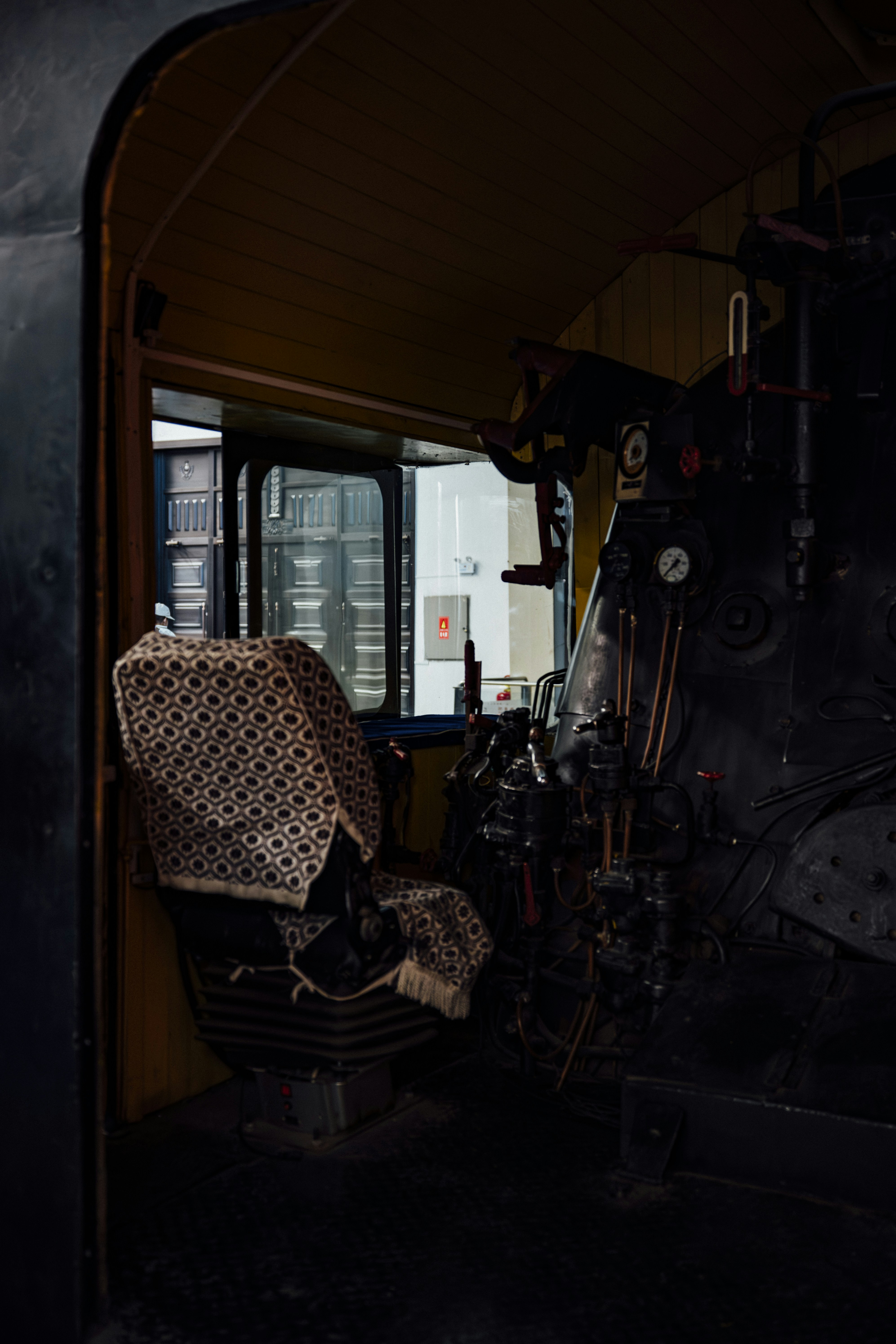 Interior view of a vintage train cabin featuring a patterned seat and intricate control mechanisms. The scene captures the essence of railway history.