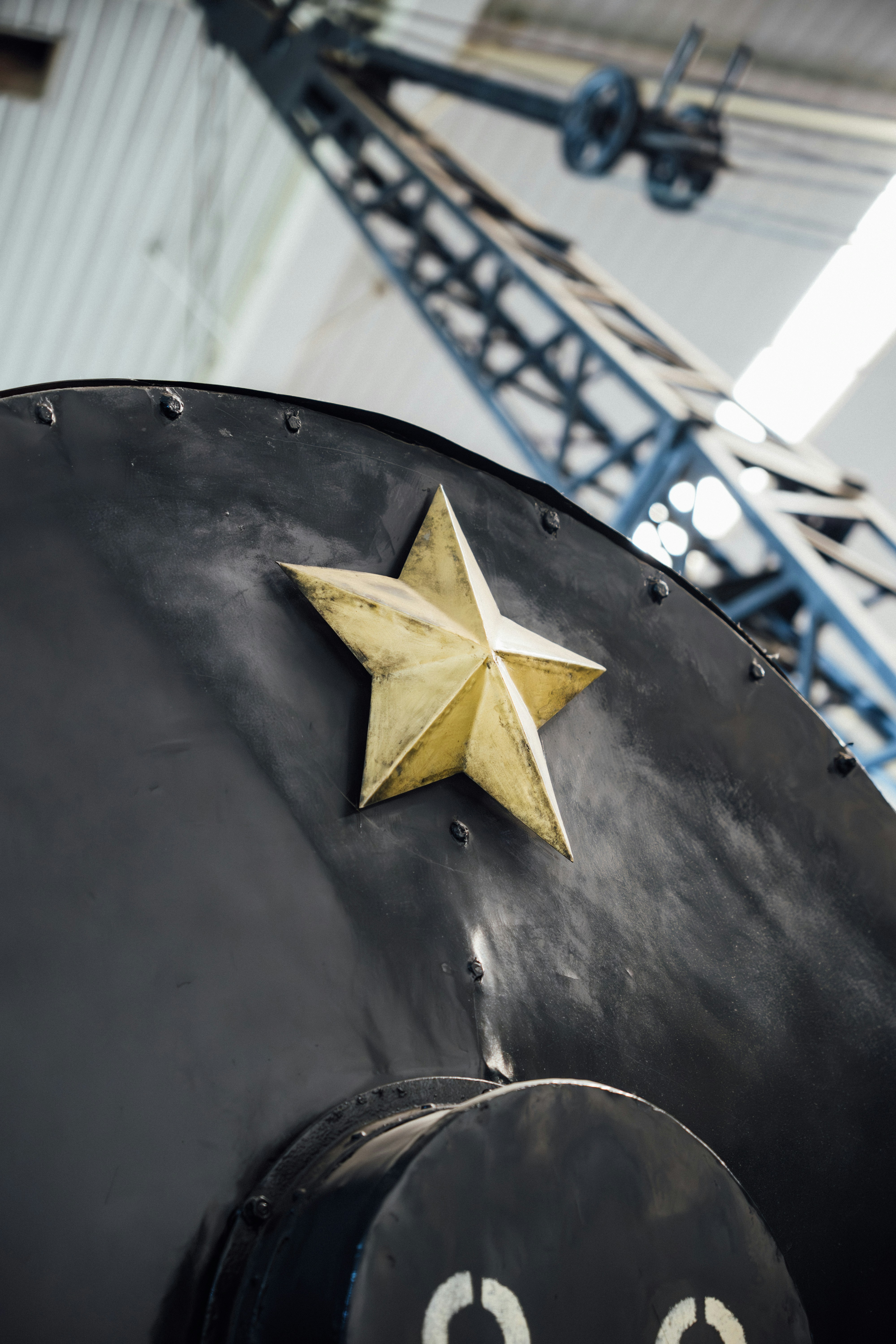 Gold Star on a Weathered Boiler, Framed by Blue Industrial Crane