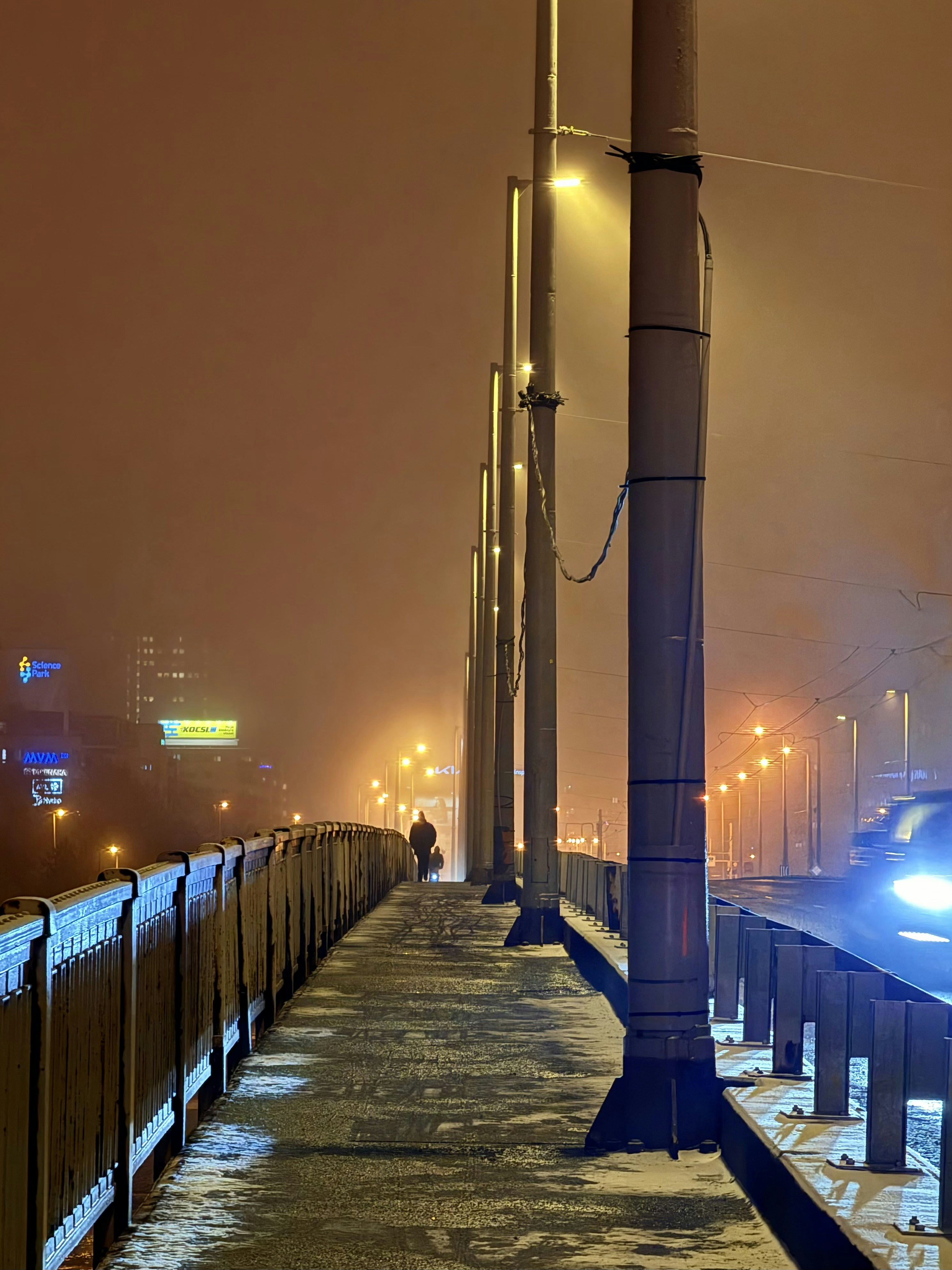 Lone silhouette on a fog-kissed bridge under amber streetlights