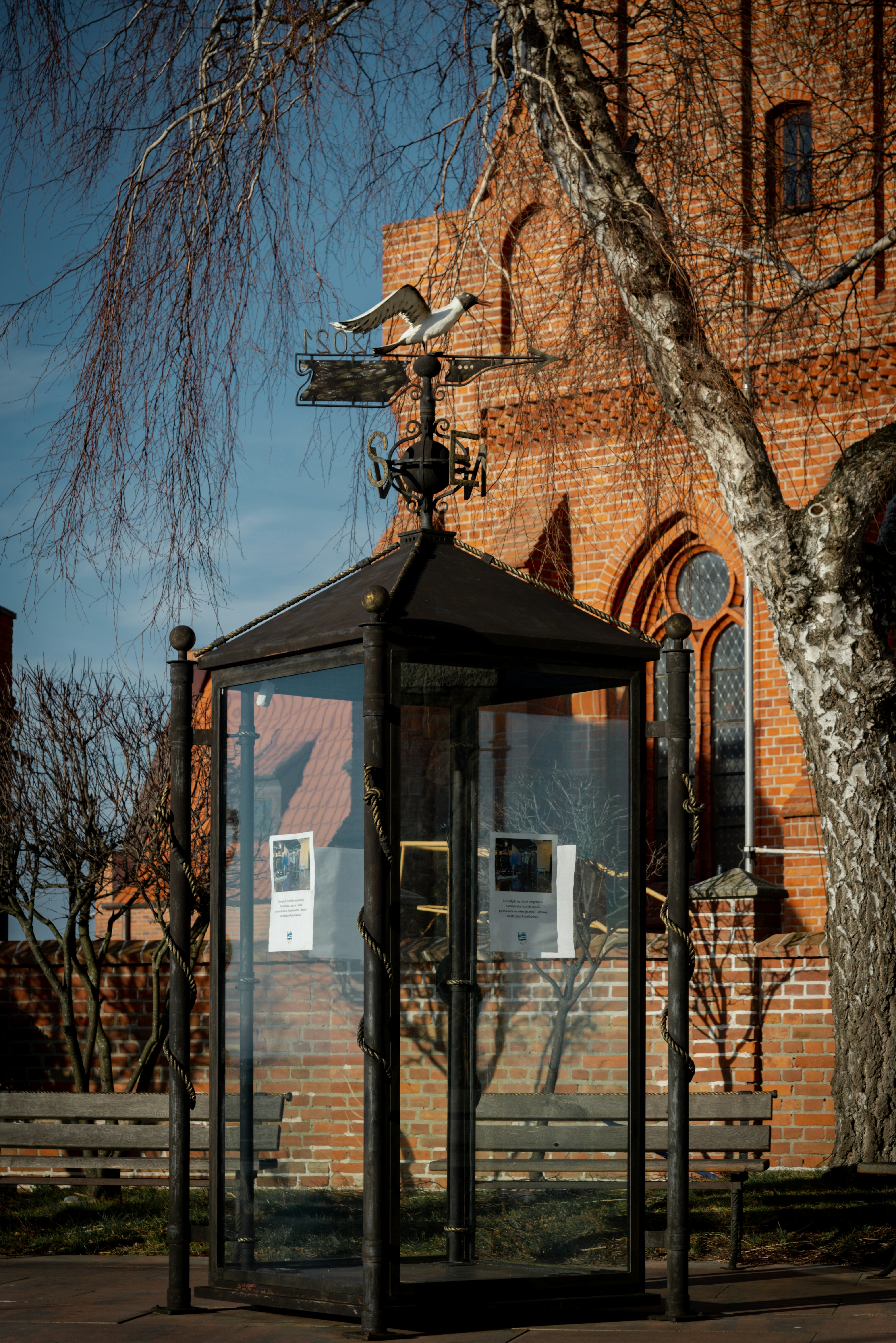 Glass Pavilion in Front of a Brick Church under Bare Trees