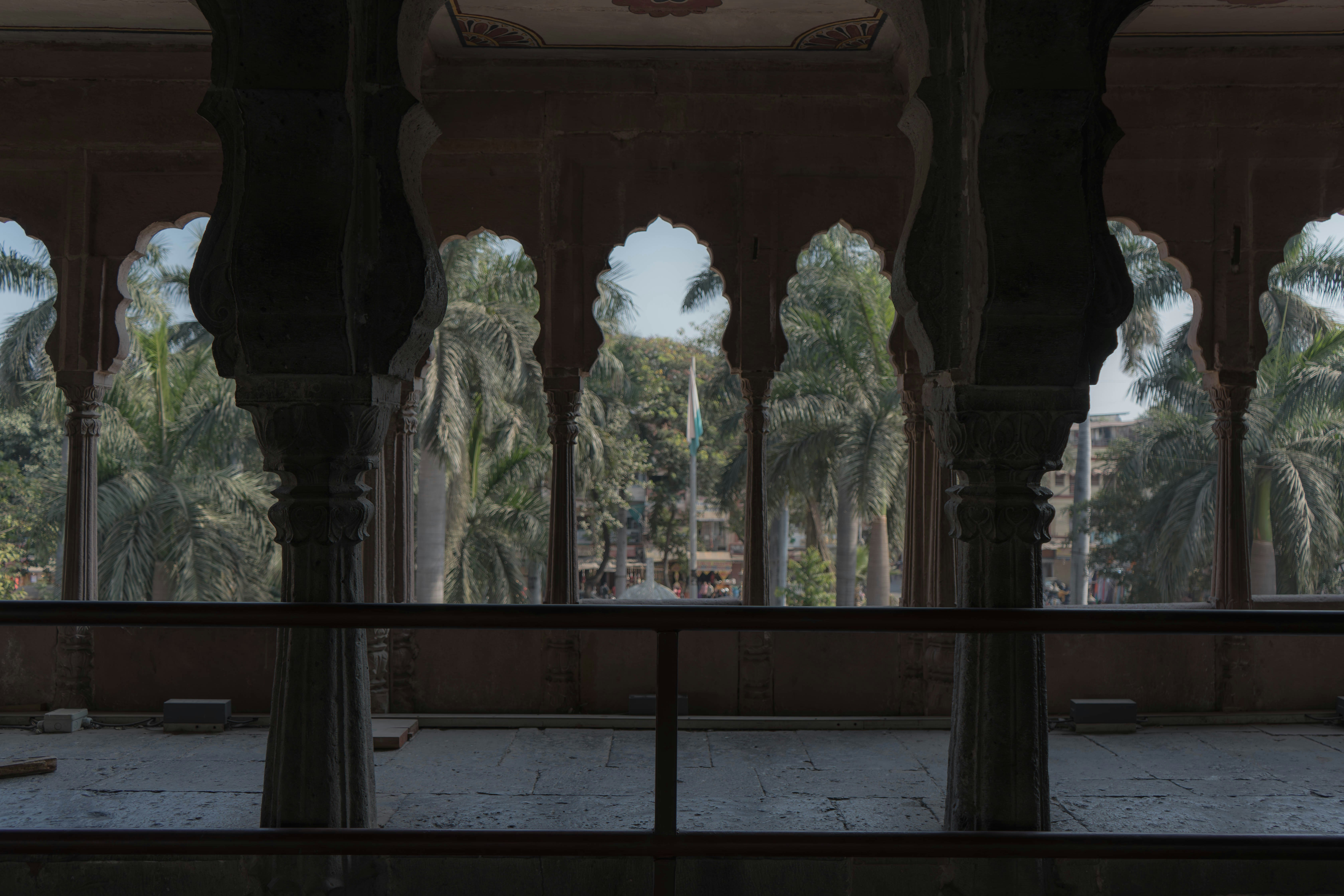 Intricate arches framing a view of palm trees and a distant flag, showcasing architectural beauty and cultural richness.