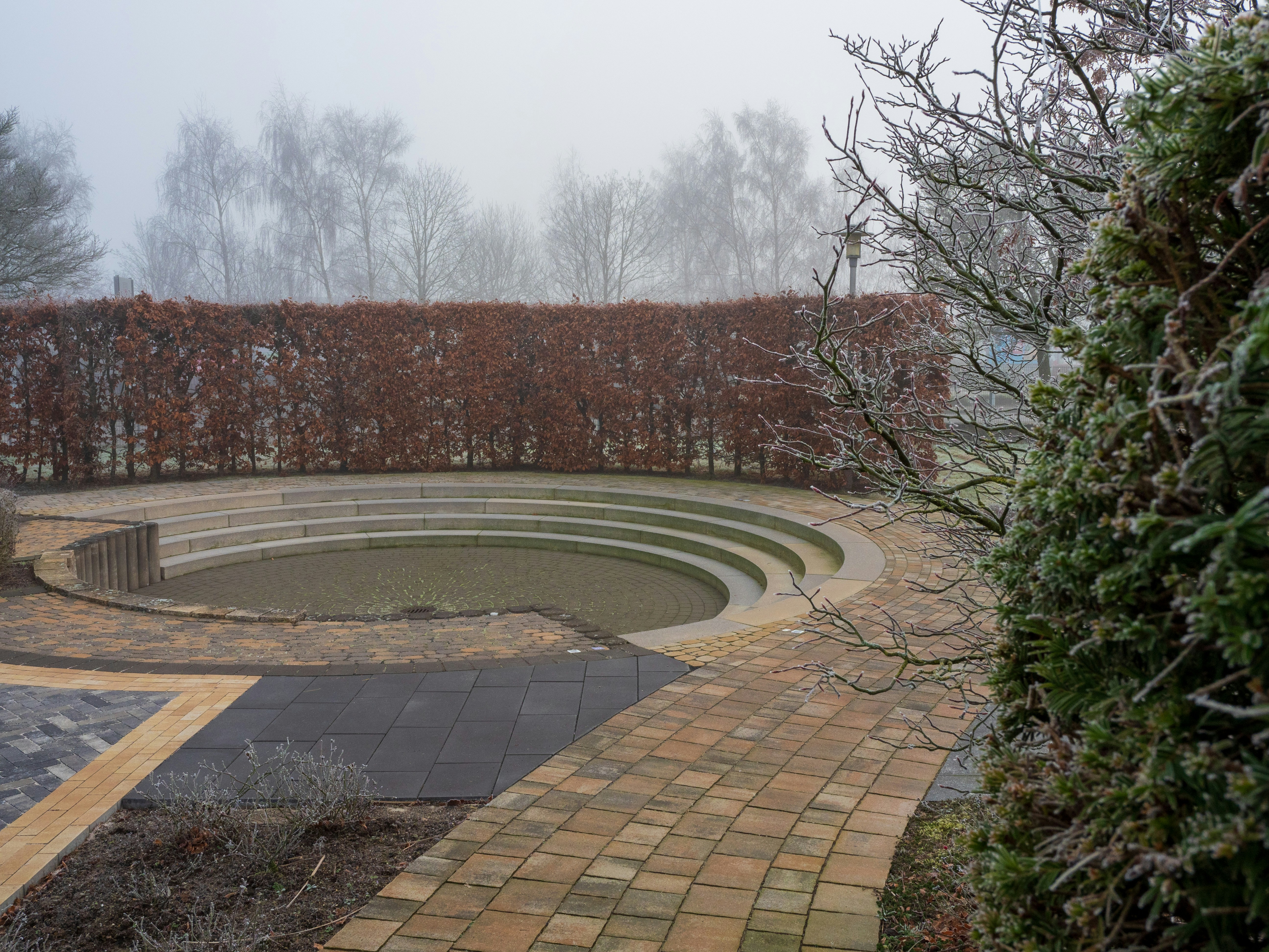 A circular stone structure surrounded by a brick walkway photo – Free ...