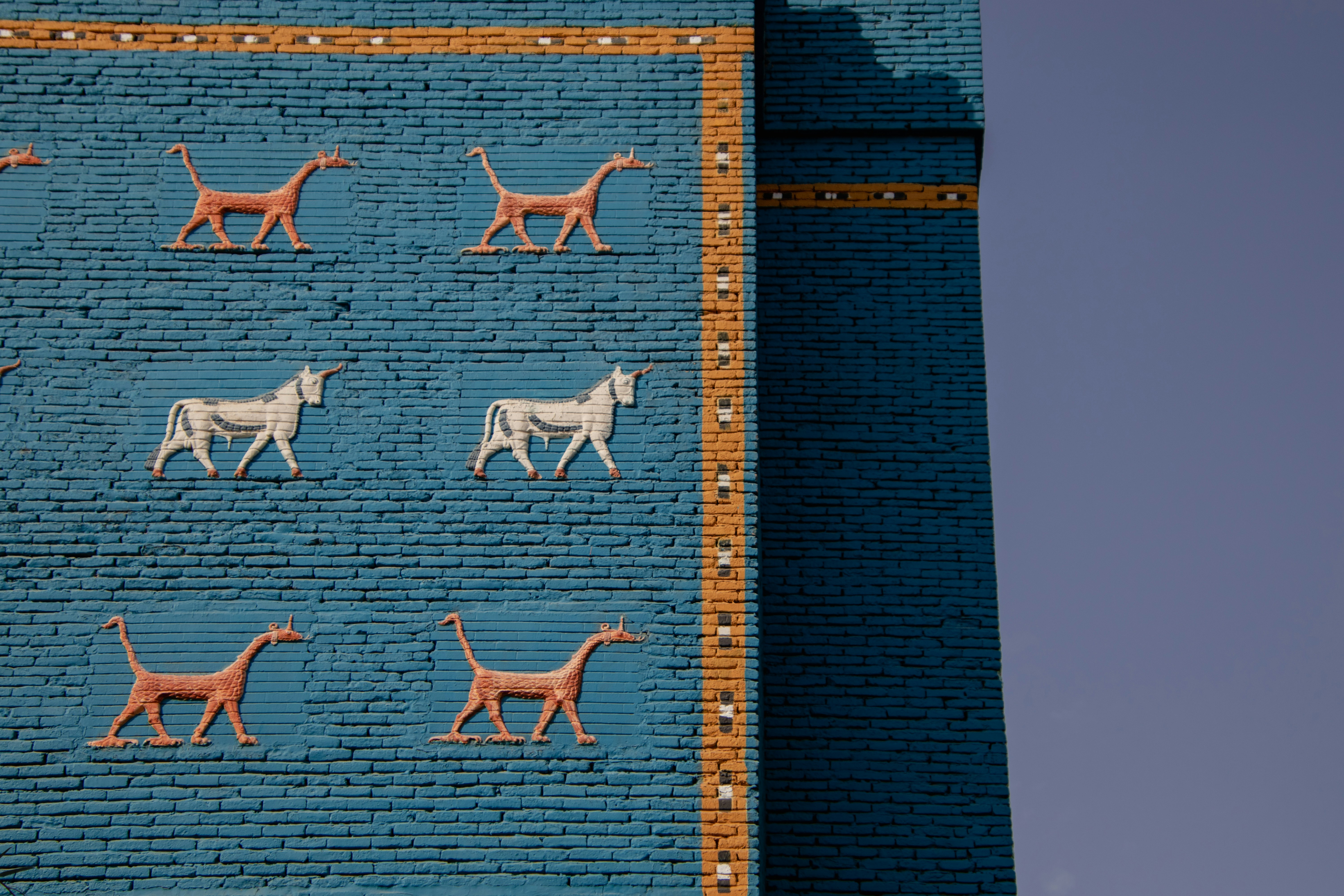 Parade of Orange Cat Silhouettes Across a Turquoise Brick Facade