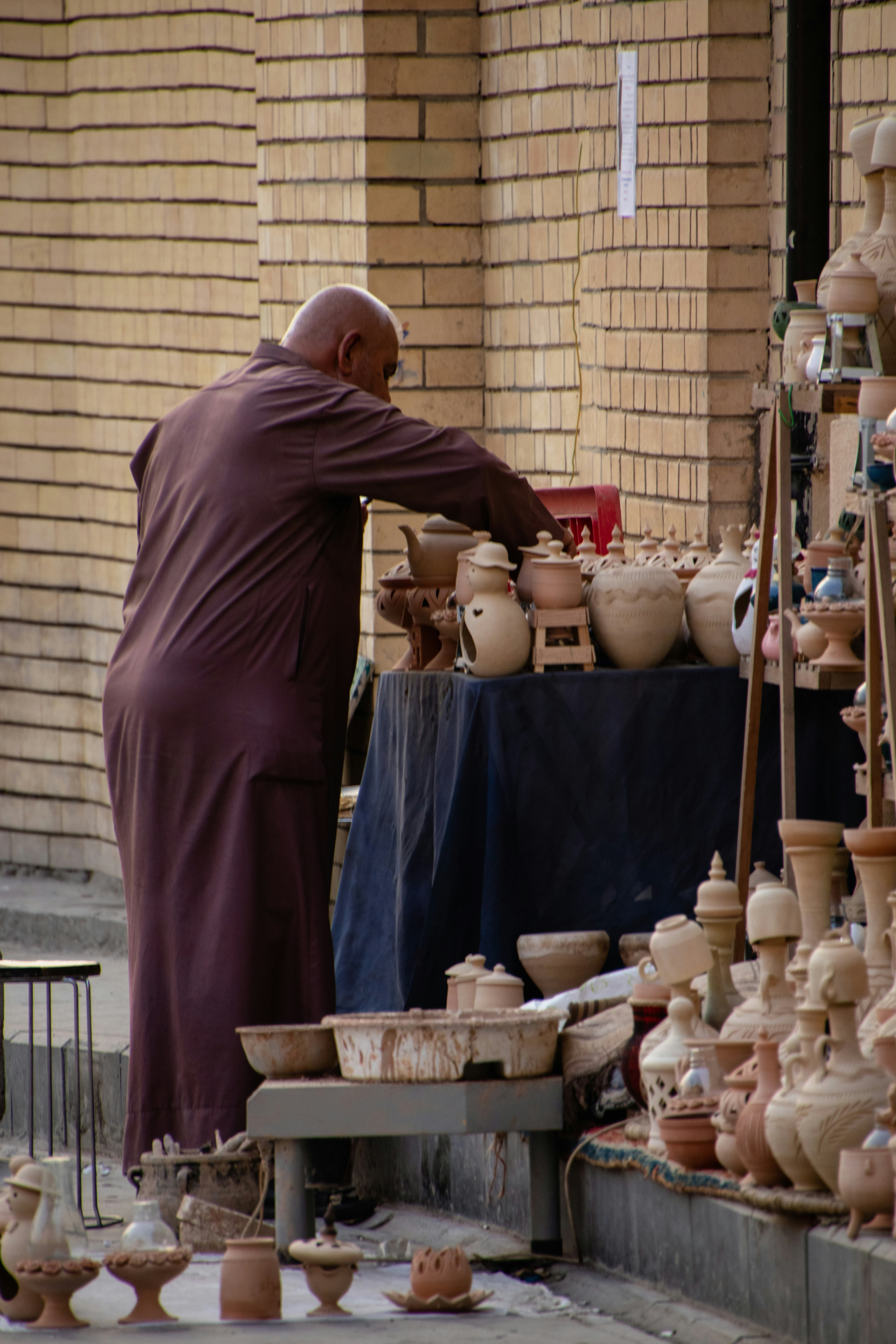 Monk at a street-market pottery stall among rows of clay pots