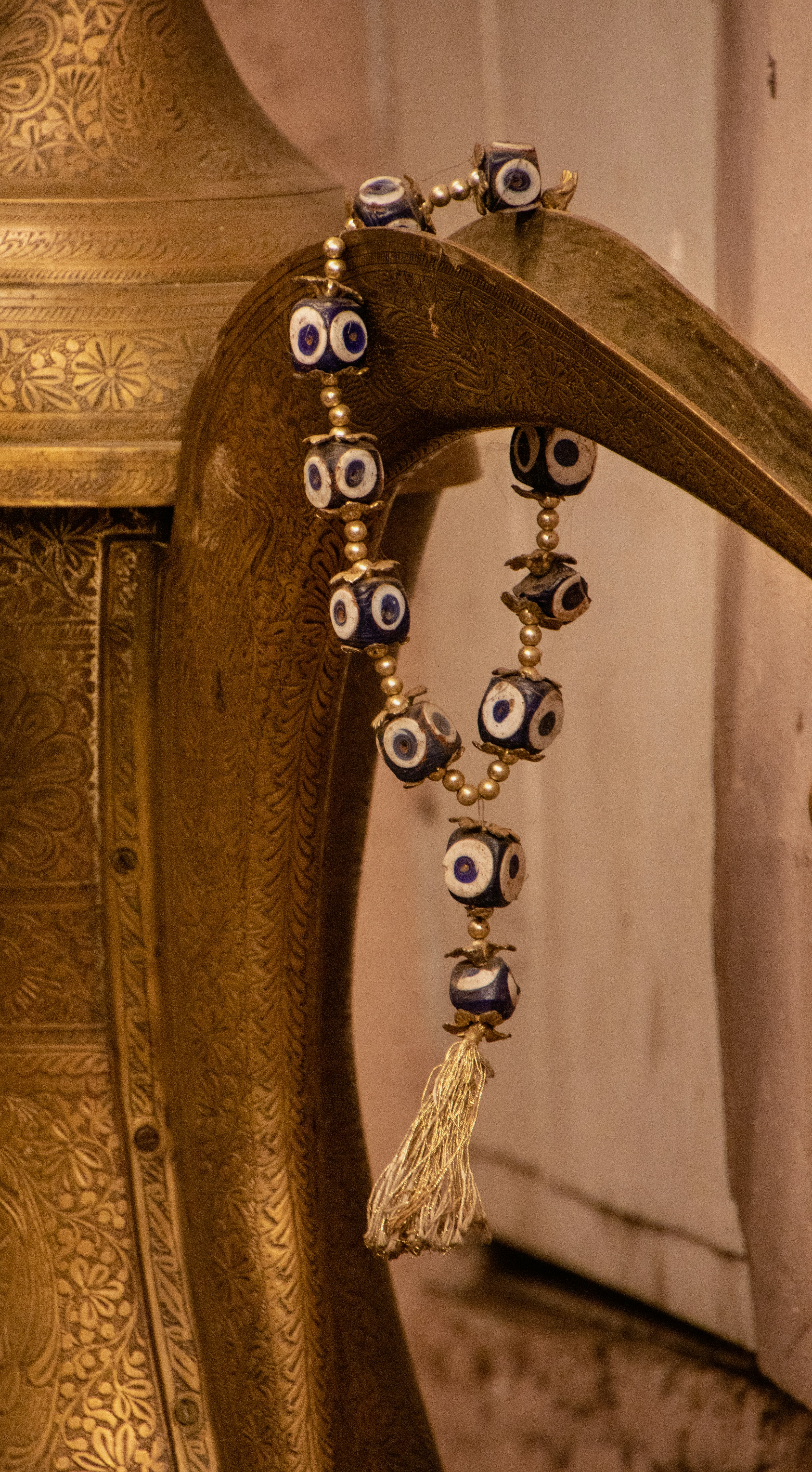 Cerulean Evil-Eye Necklace Draped Across an Ornate Brass Scroll