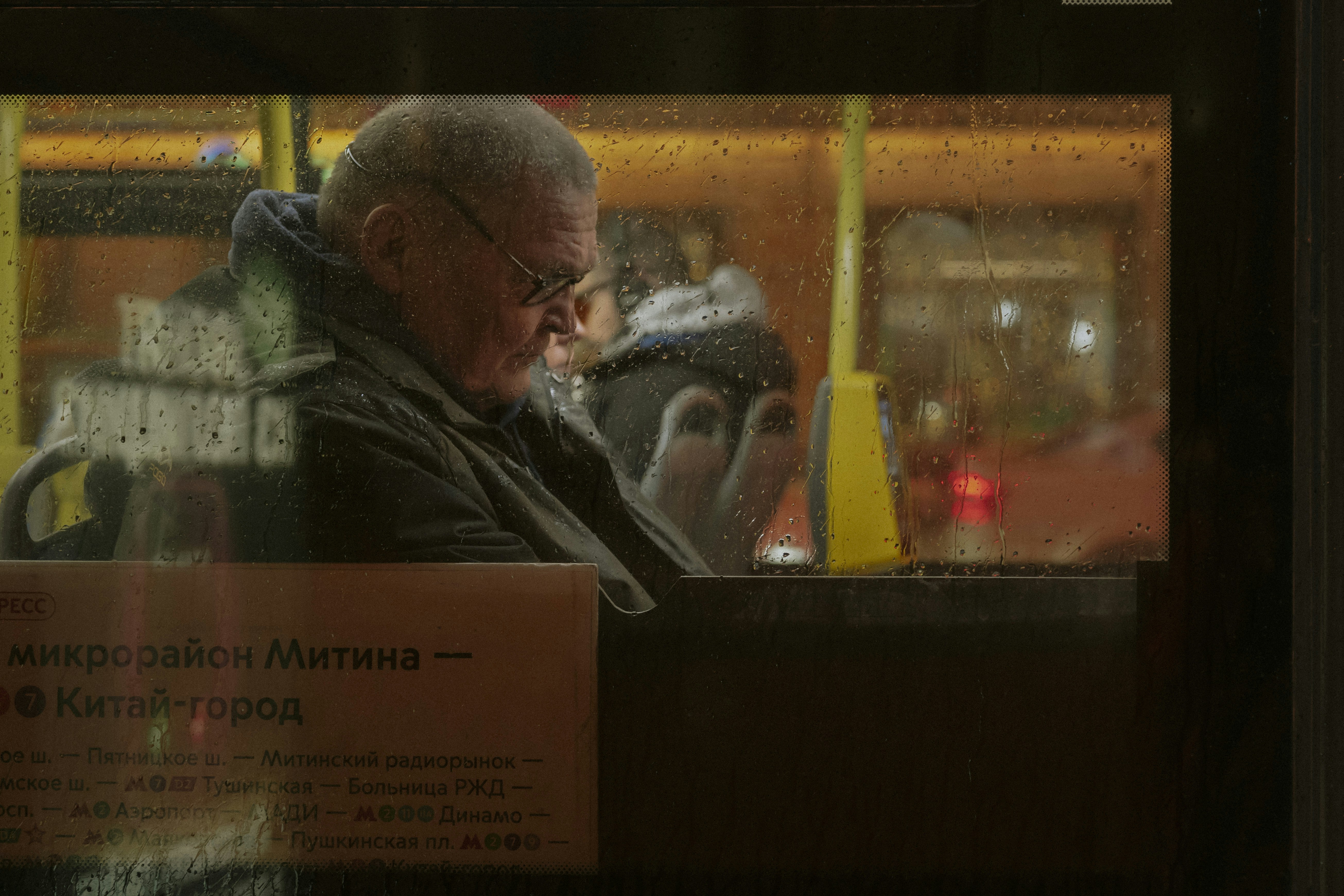 Windowed Quiet: A Seated Passenger Amid Reflections on a Dim City Bus