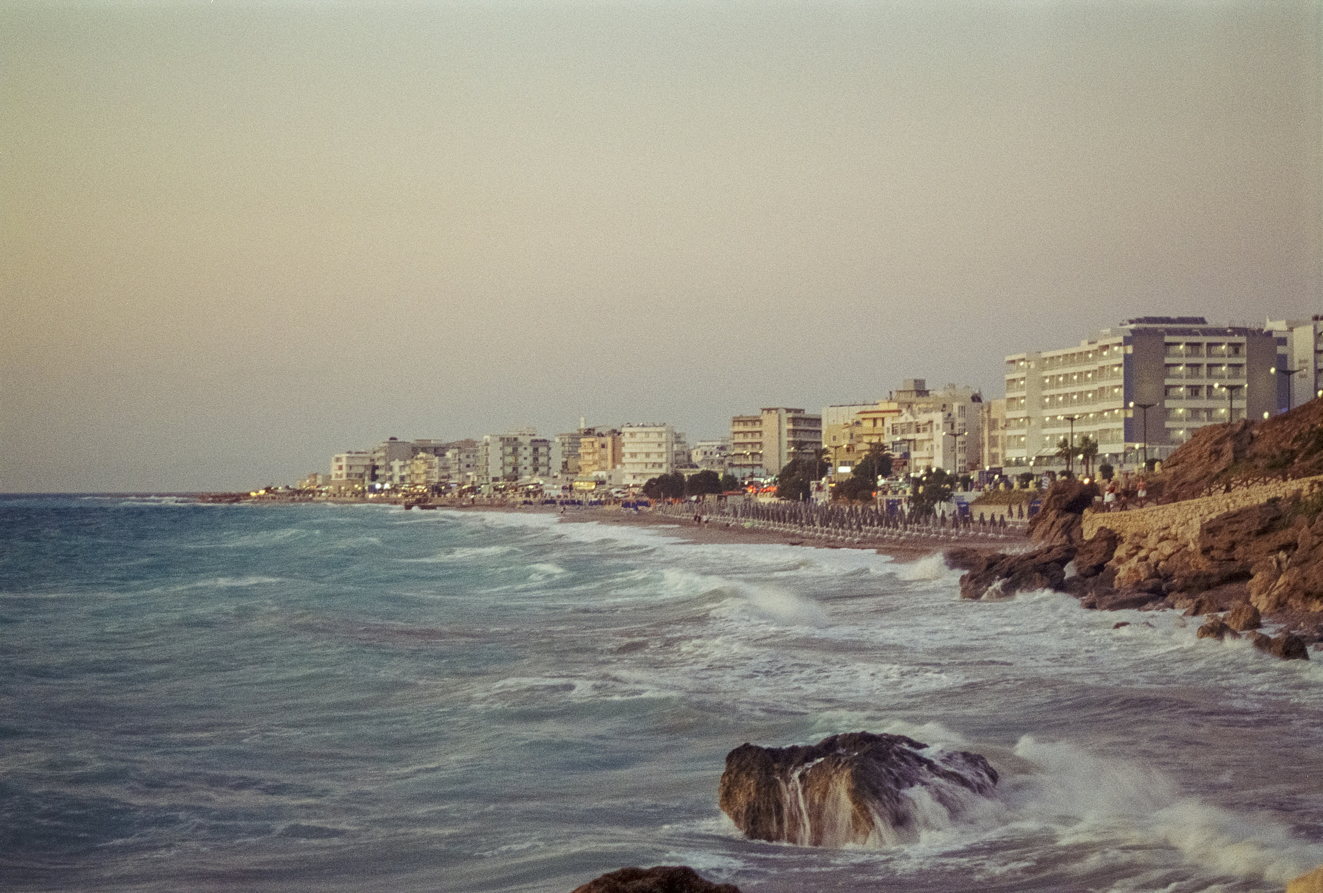 Pastel Promenade by the Sea: Coastal Cityscape with a Rocky Foreground