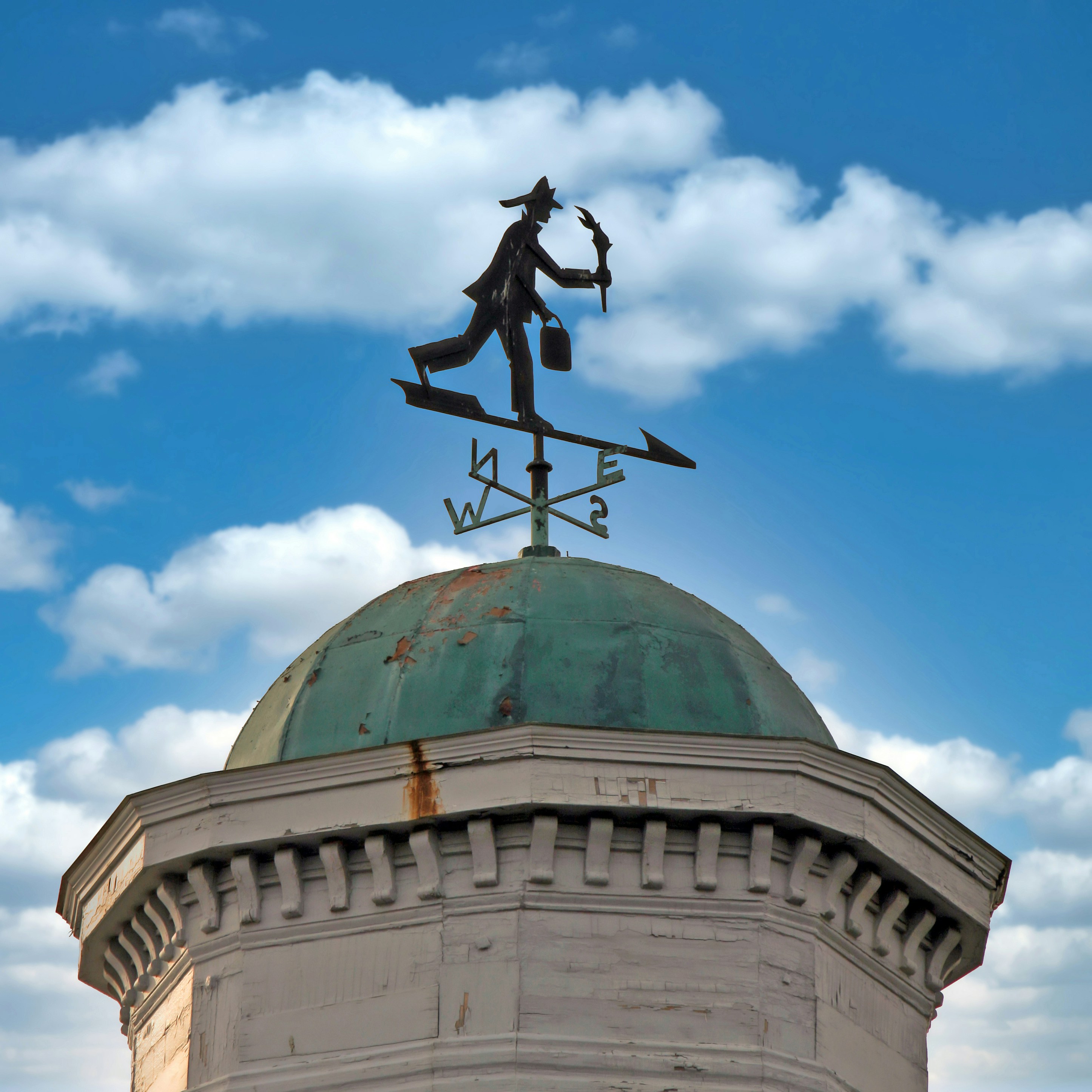 "Fire Fighter Weather Vane" --- A firefighter weather vane on top of a building's cupola.