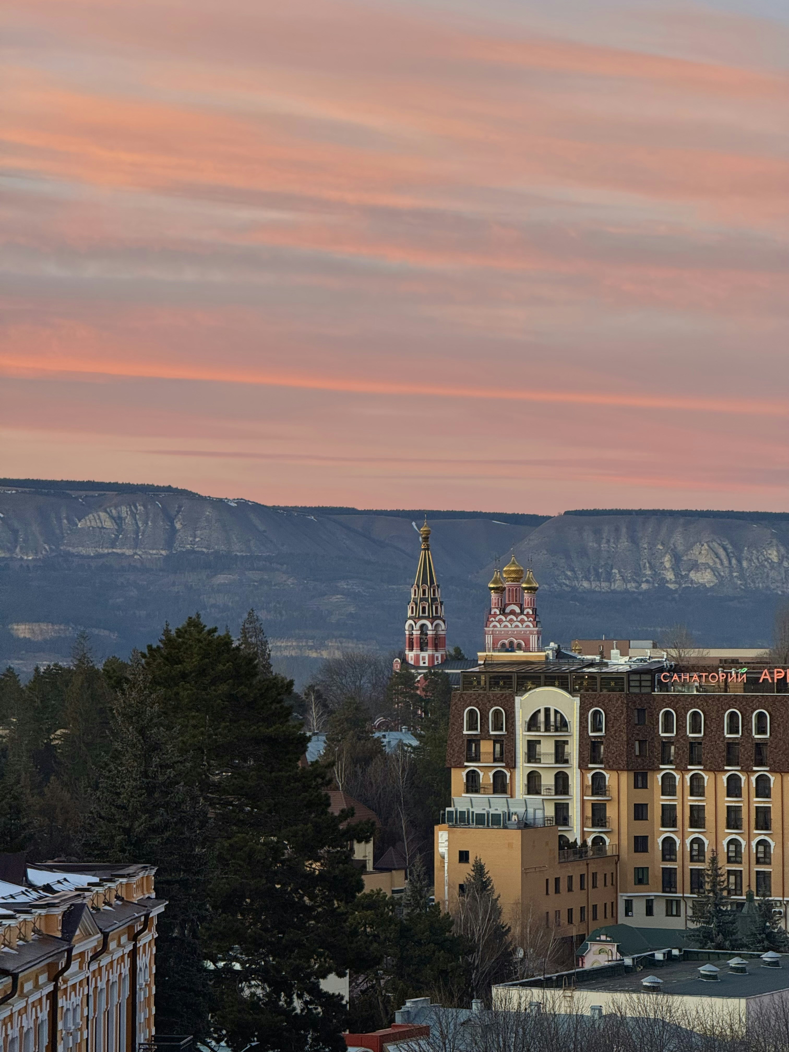 Cityscape with historic buildings under a vibrant sunset sky.