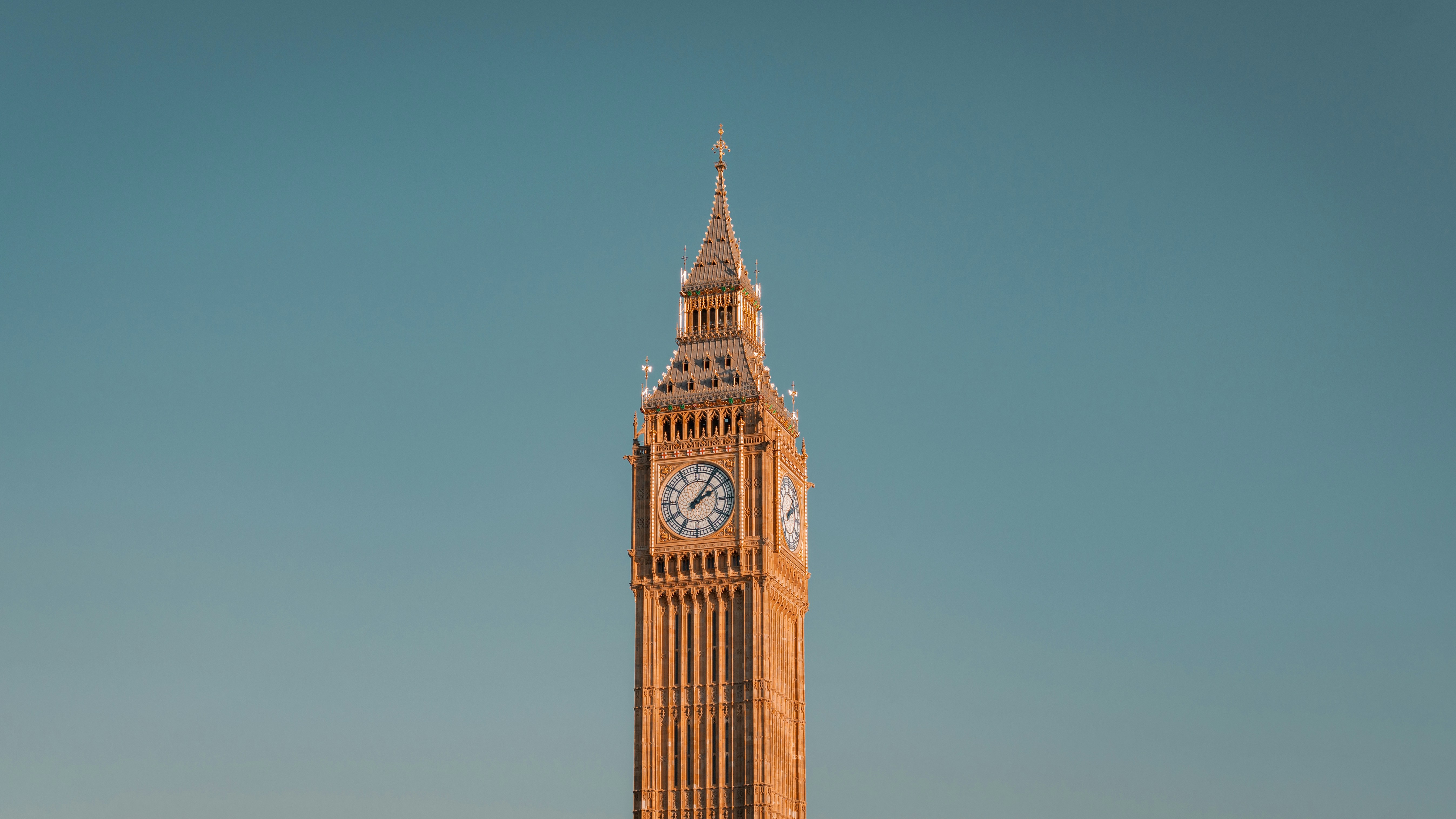 Sunlit clock tower against a clear blue sky.